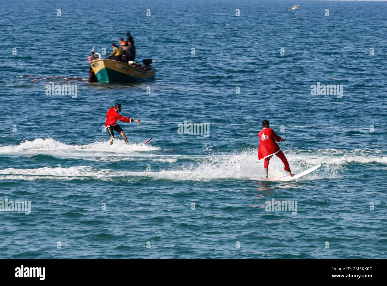 Palestinian surfer dressed in a Santa Claus outfit rides near a fishing ...