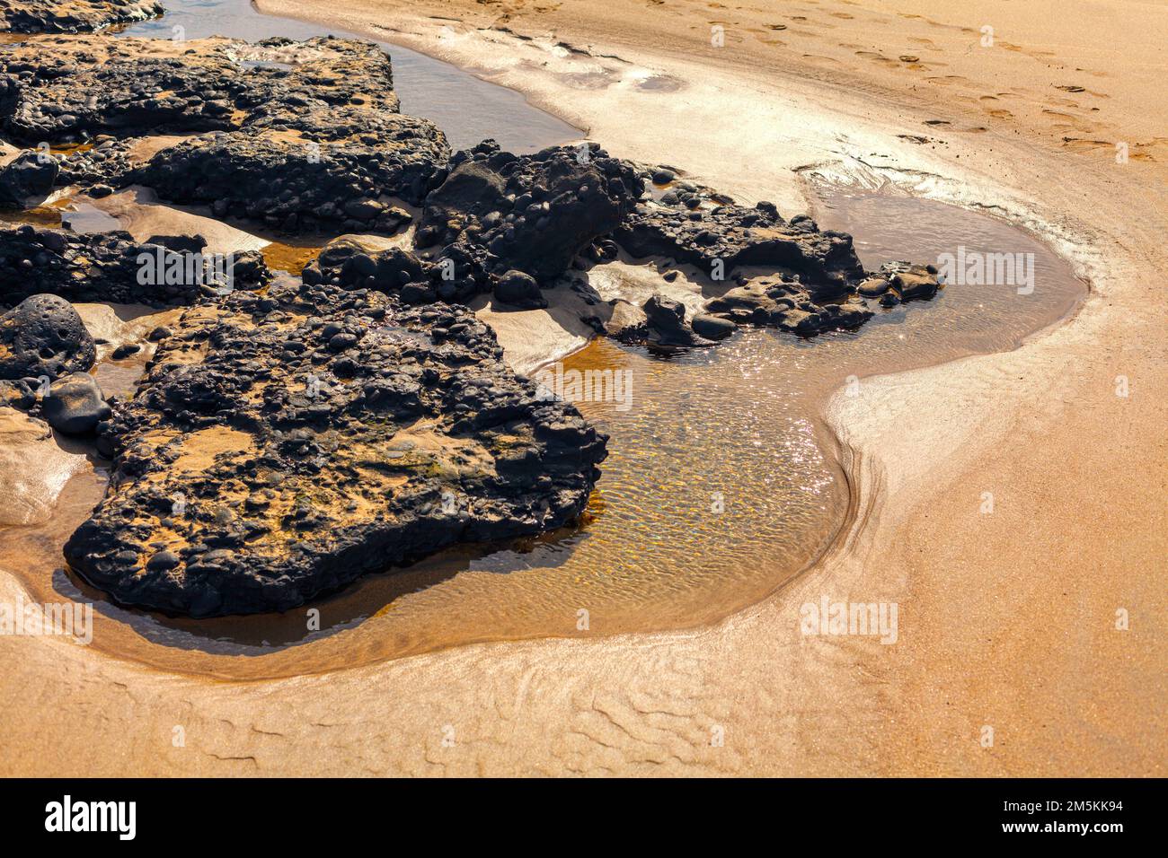 Coastal rocks and sand . Beach with wet sand Stock Photo - Alamy