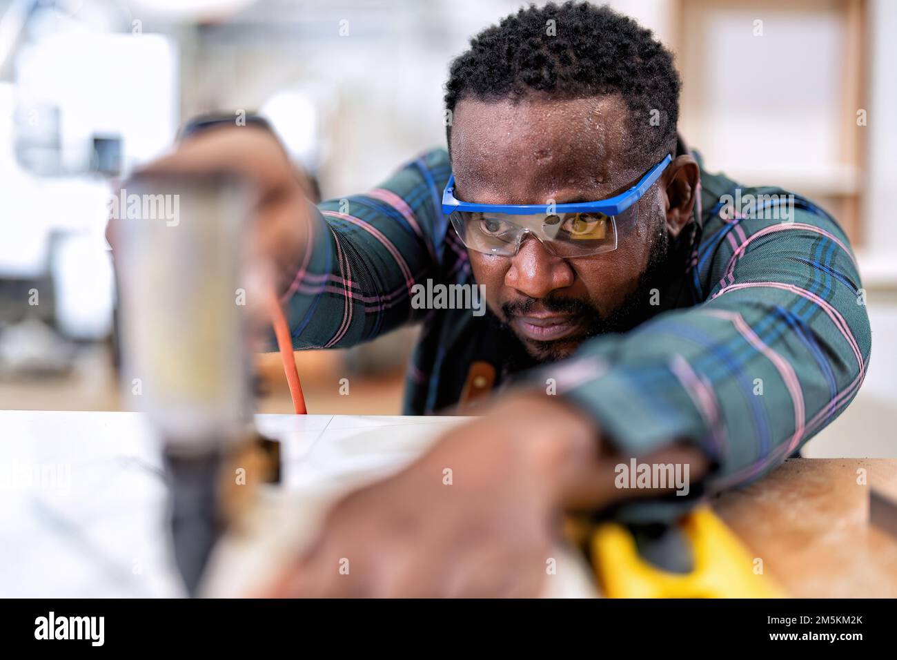 In work place carpenter man concentrate working using pneumatic nail gun drive nail to the wood ...