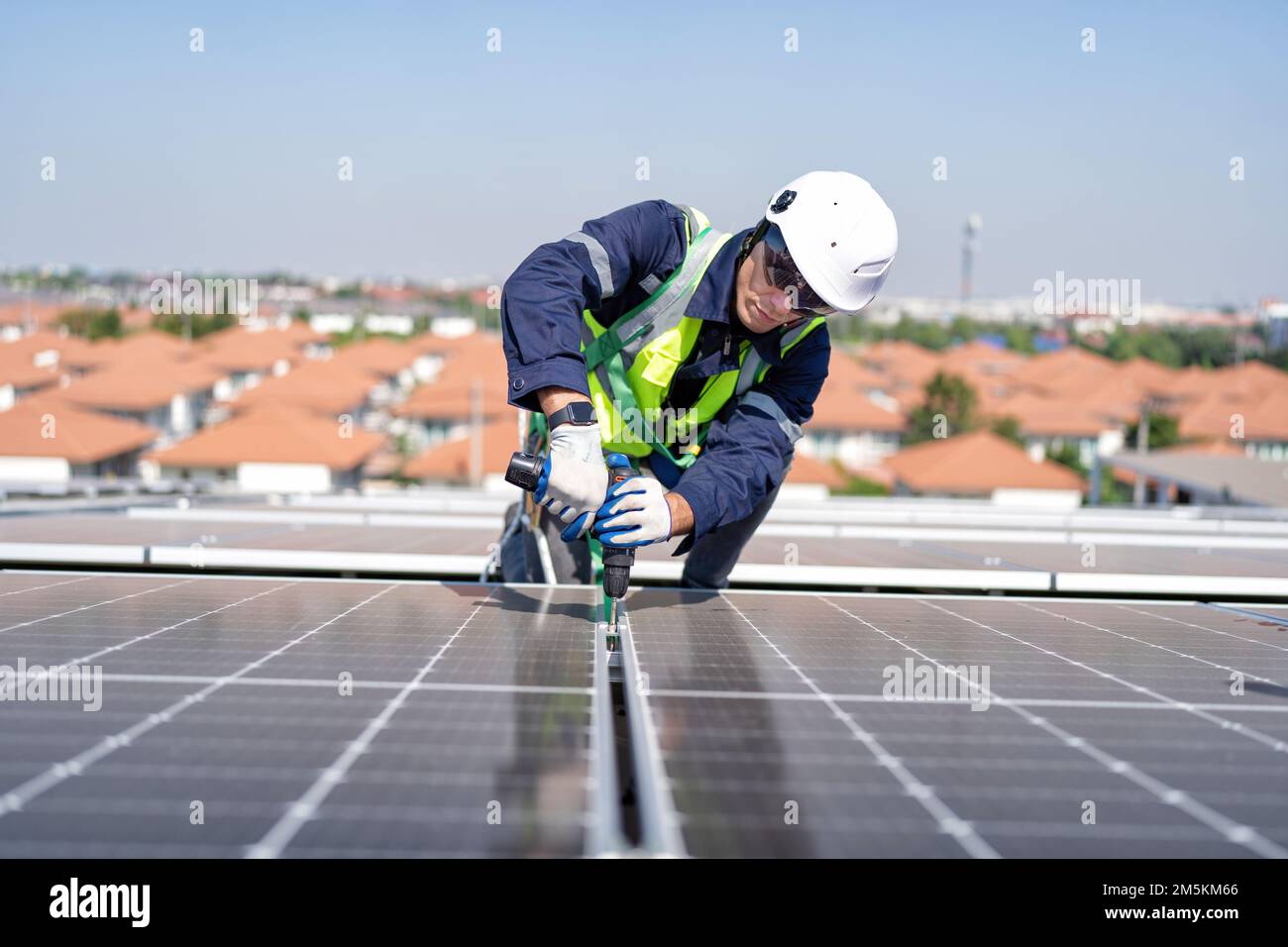 Engineer on rooftop kneeling next to solar panels photo voltaic with ...