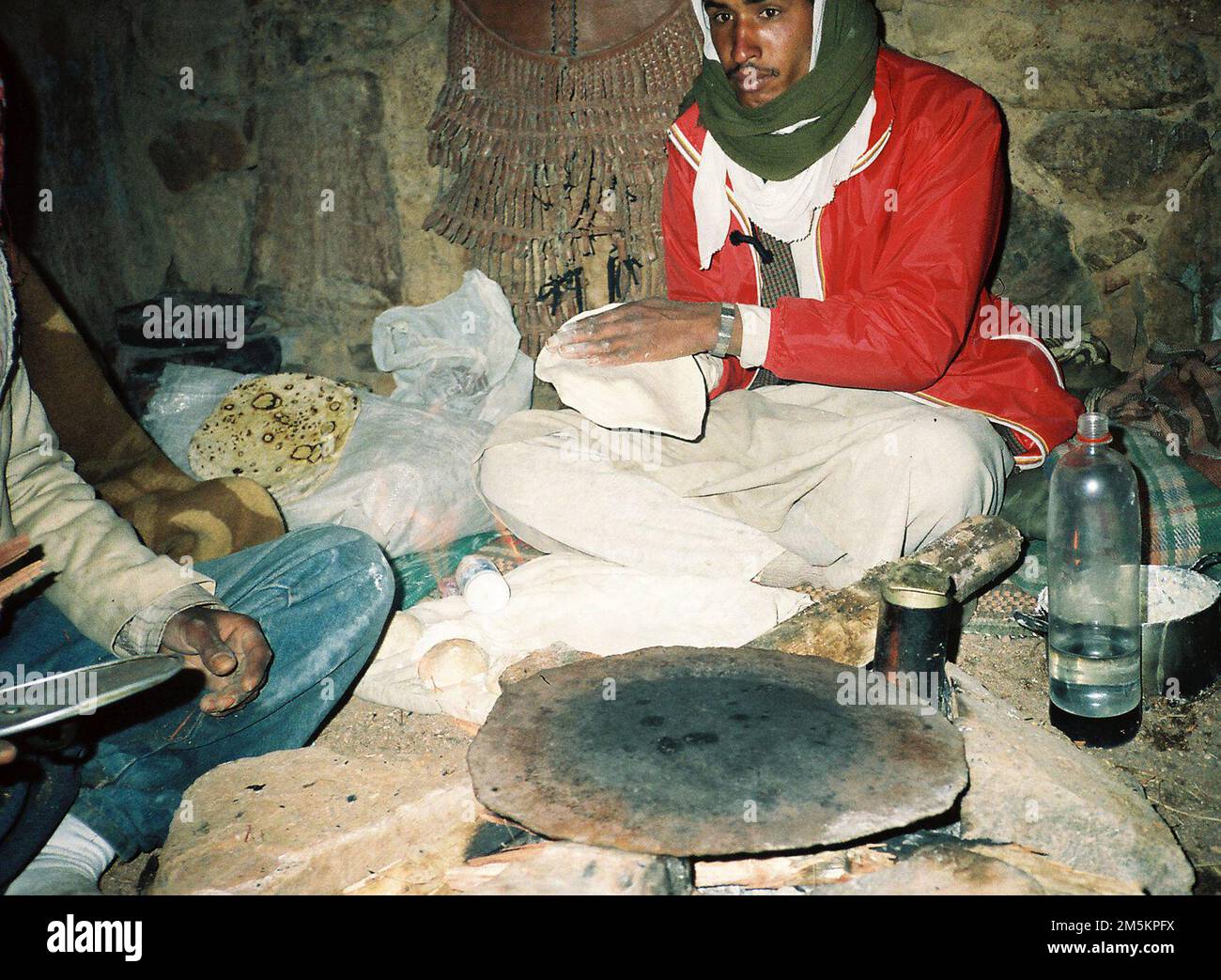 A Bedouin man preparing traditional Bedouin bread in a camp during a ...