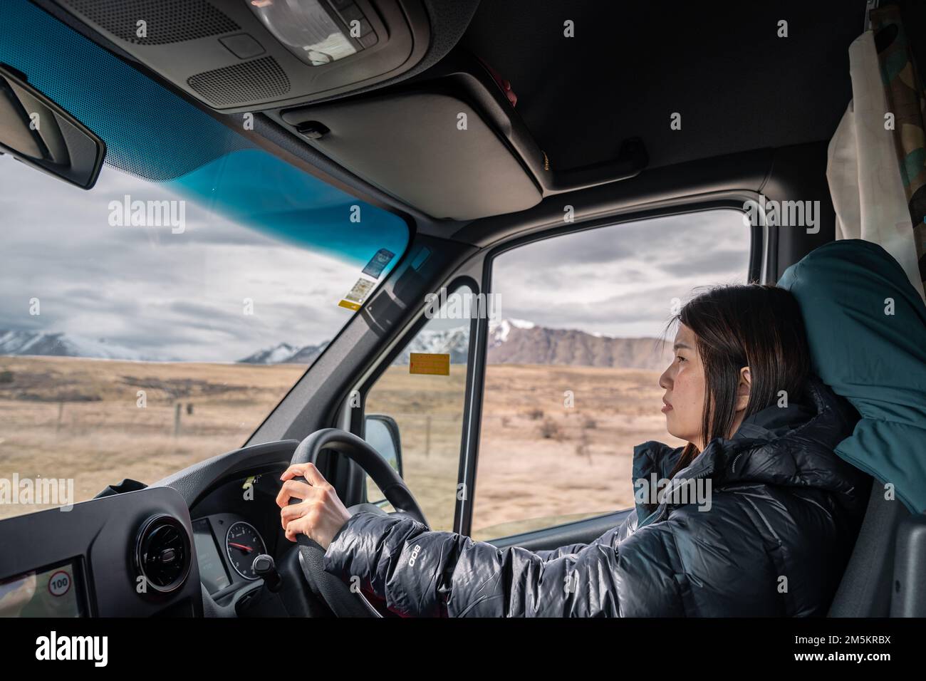 Female traveler drive camper van on empty mountainous road. New Zealand ...