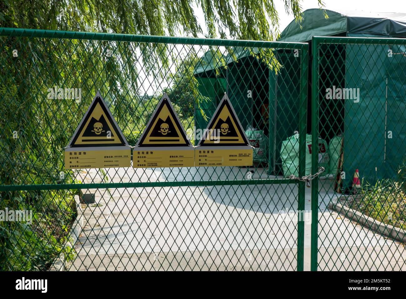 A closeup of three signs of Hazardous Waste Area on a factory gate in ...