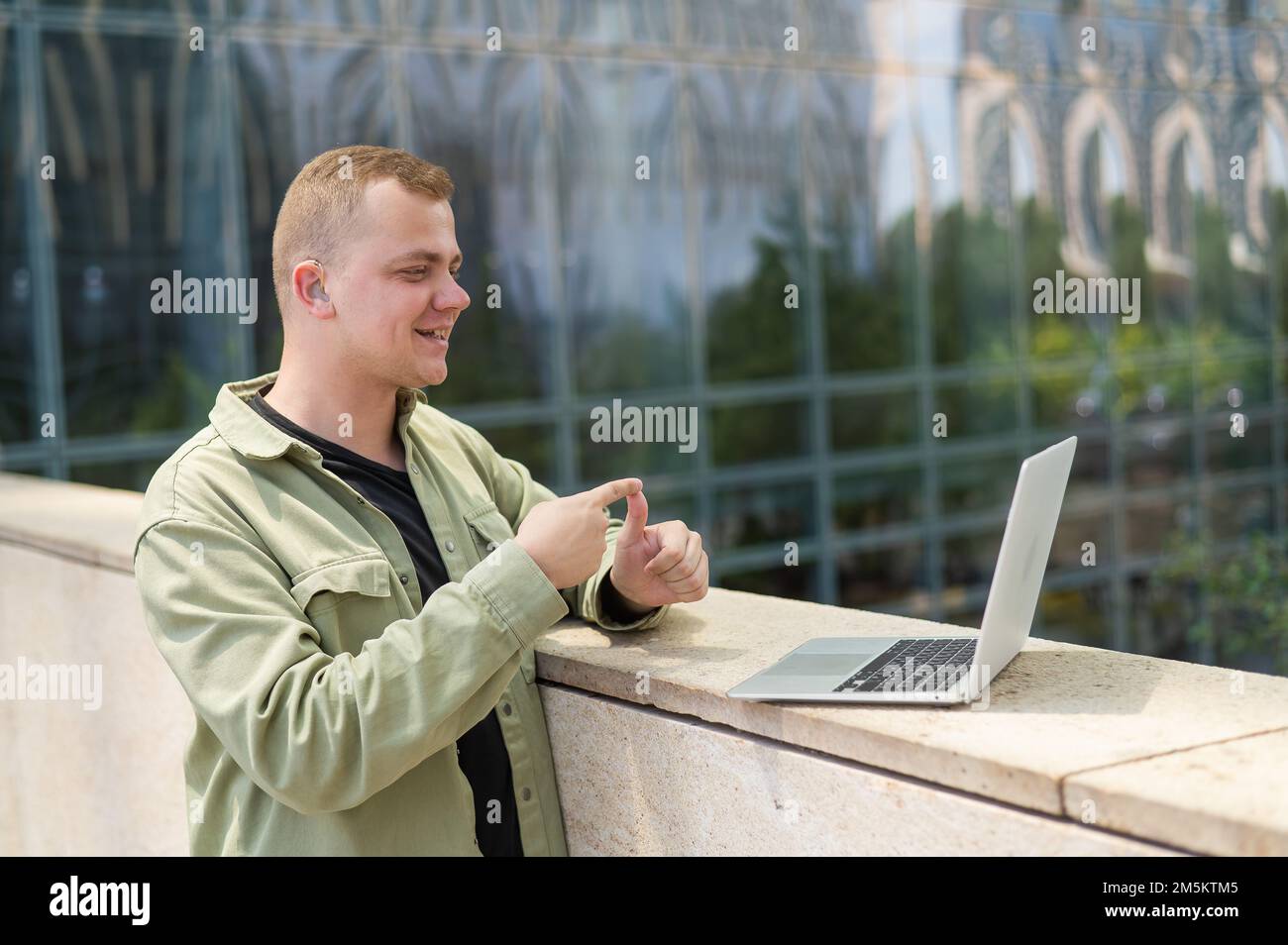 Caucasian man communicates in sign language via video link on laptop ...