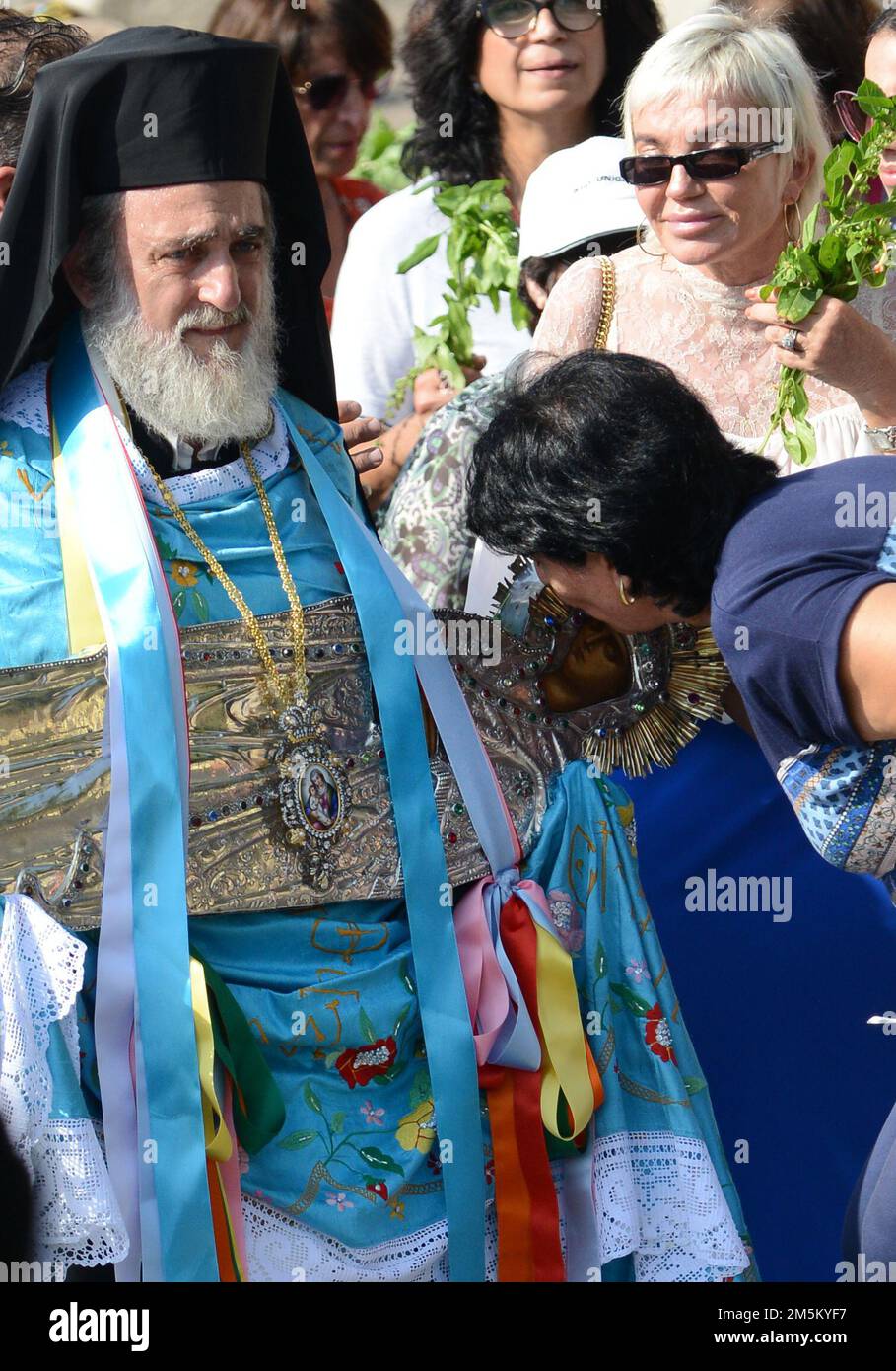 A Greek Orthodox priest carrying a silver icon of the Virgin Mary ...