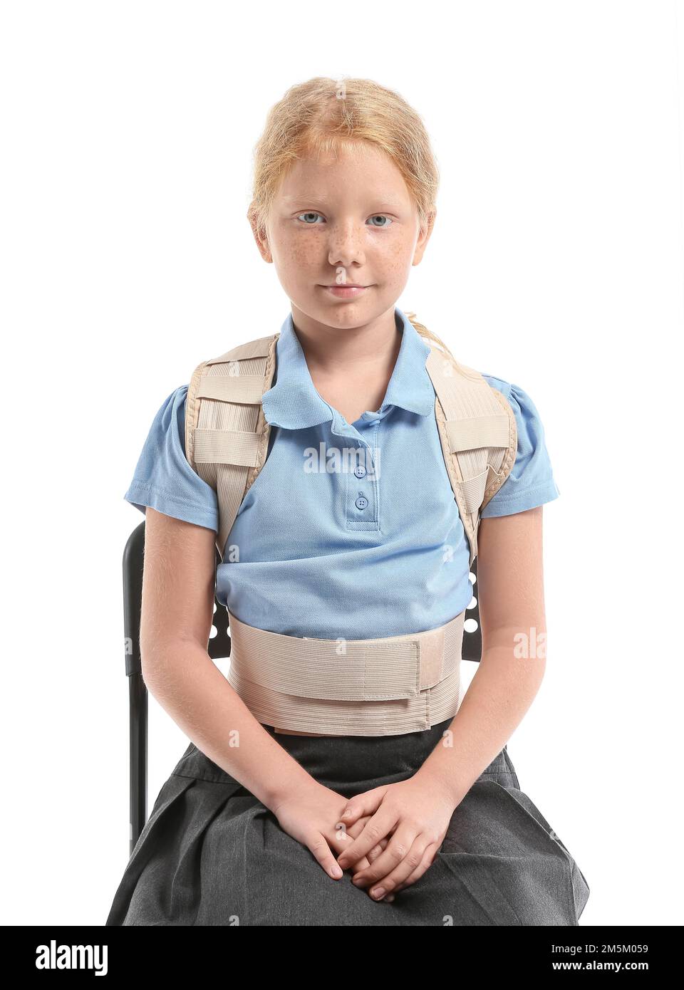Little schoolgirl in back brace sitting on white background Stock Photo ...