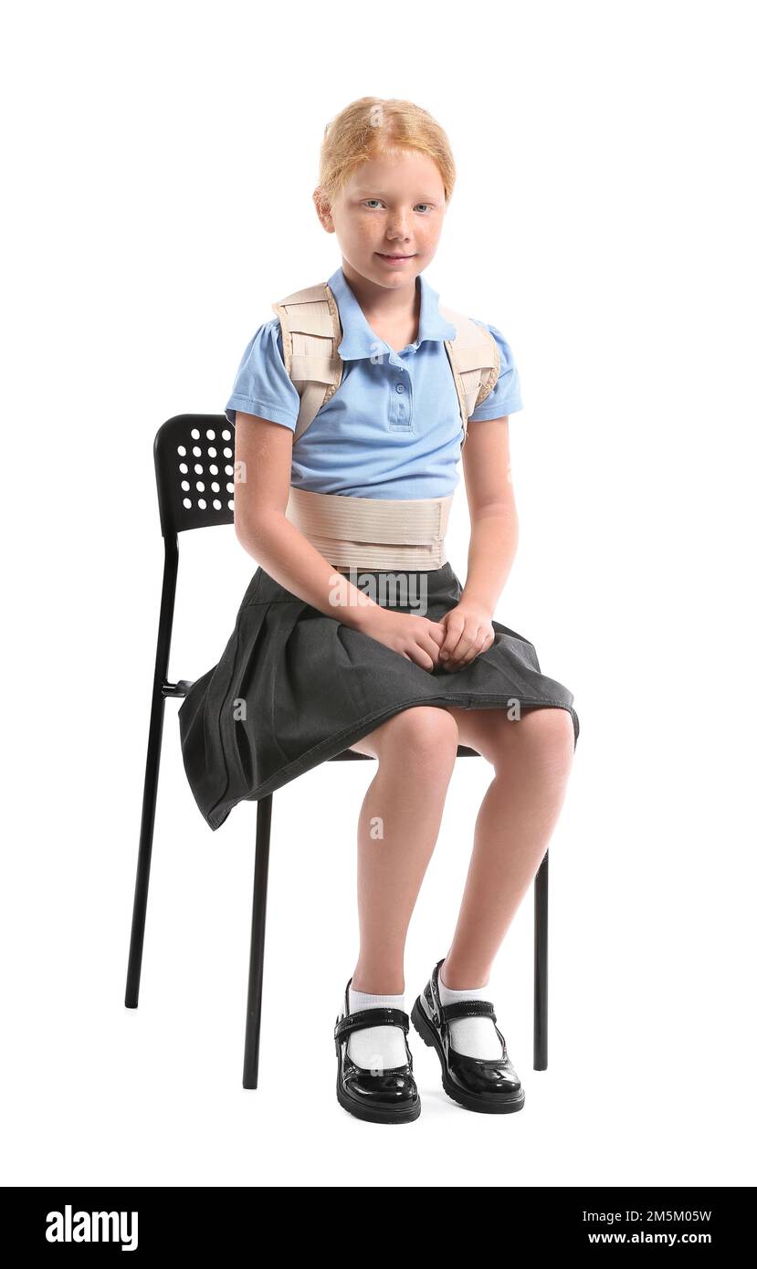 Little schoolgirl in back brace sitting on white background Stock Photo ...