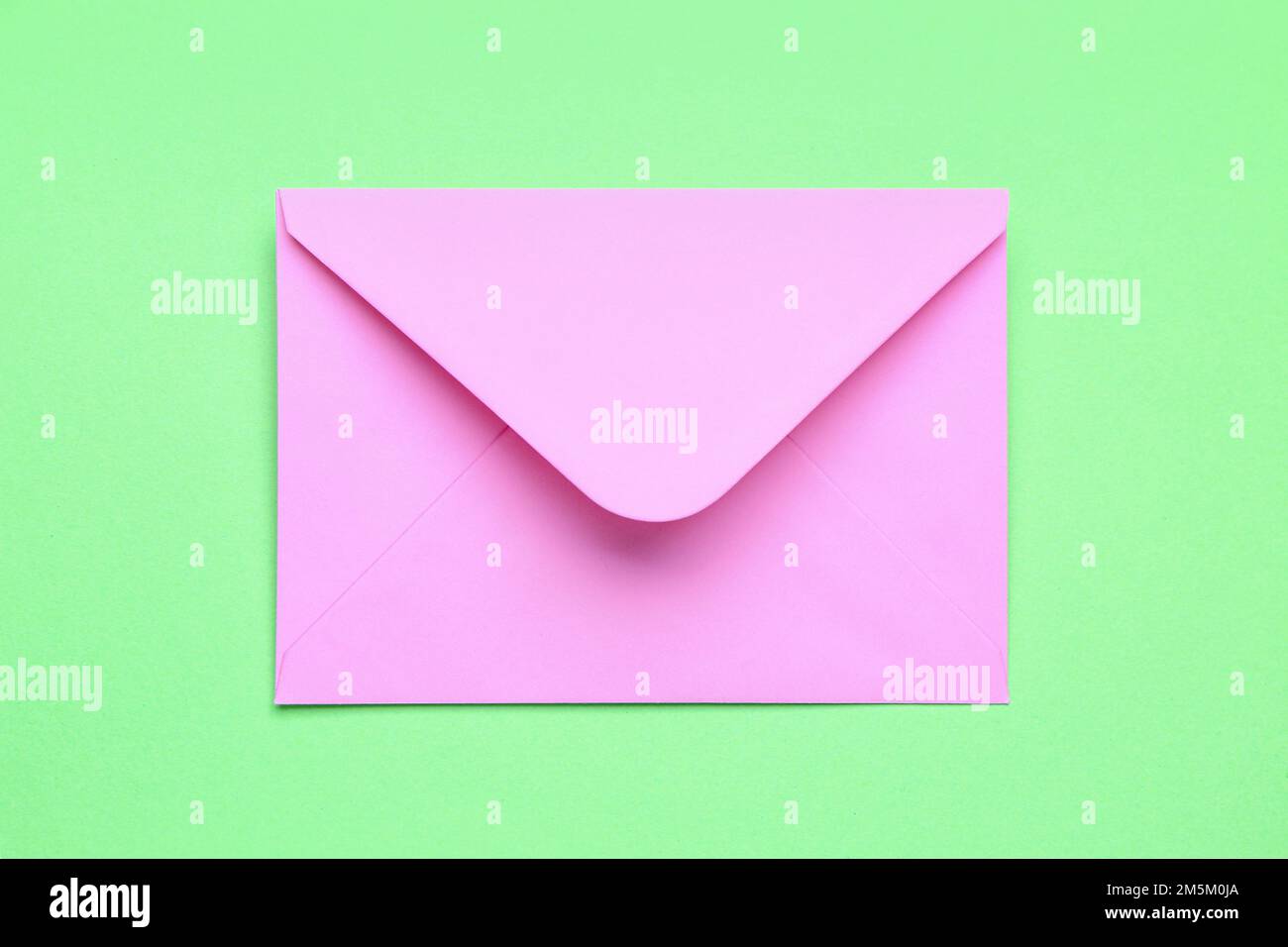 Pink paper envelope on green background Stock Photo - Alamy