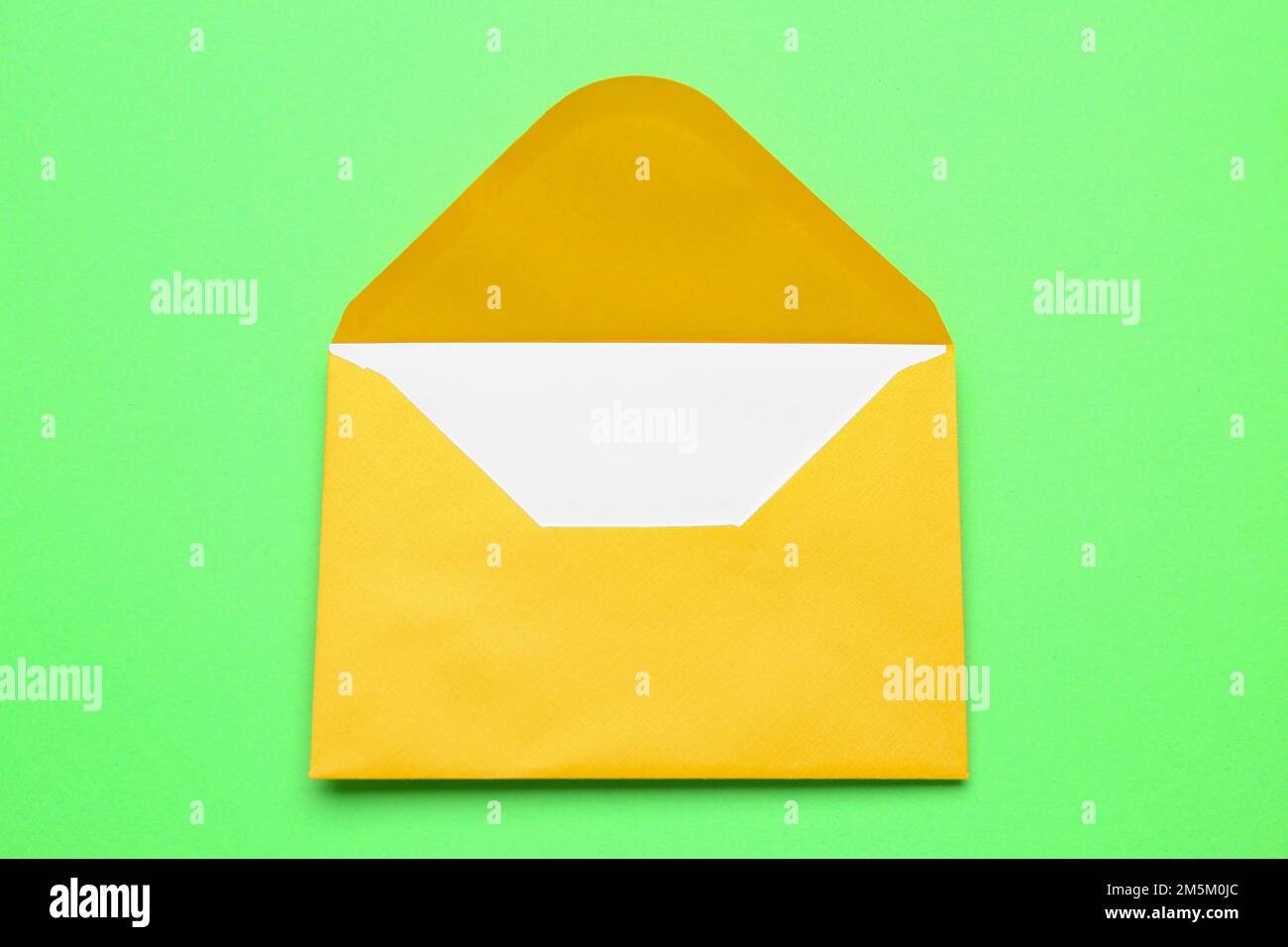 Yellow paper envelope with card on green background Stock Photo - Alamy