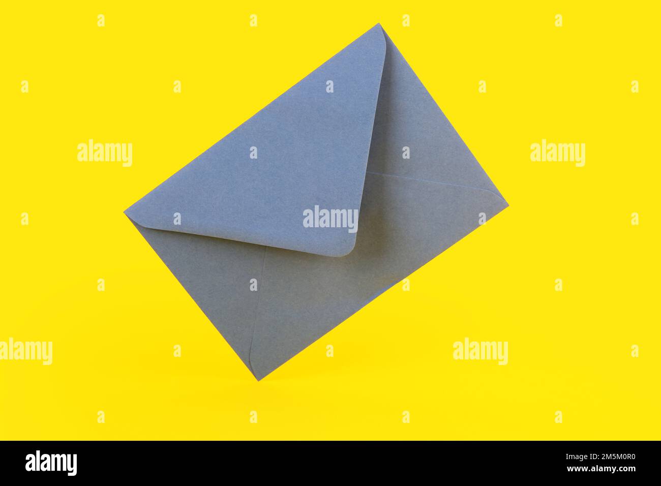 Blue paper envelope on yellow background Stock Photo - Alamy