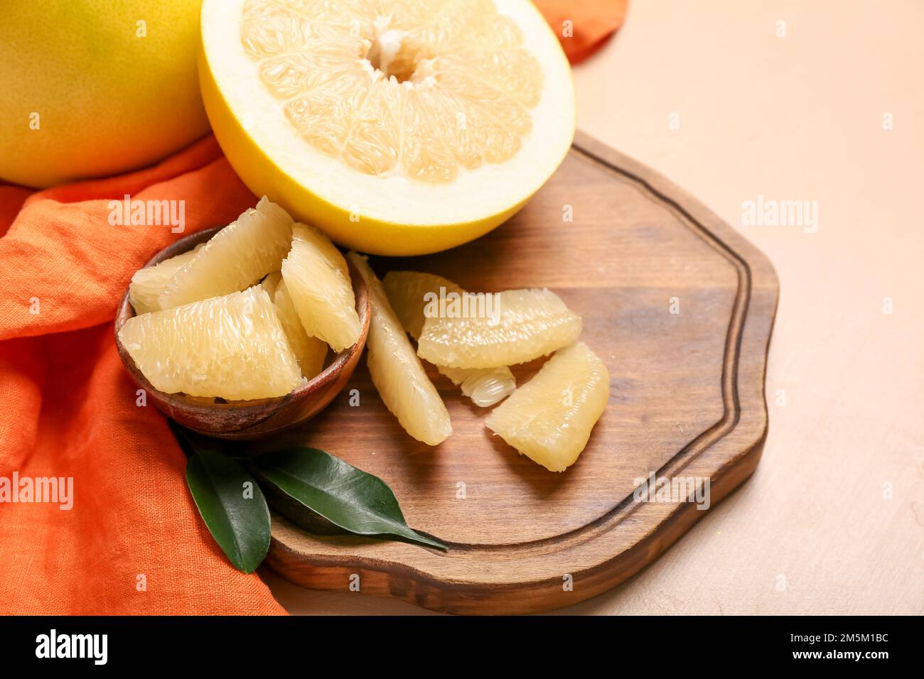 Wooden board with pomelo fruit on beige background, closeup Stock Photo ...