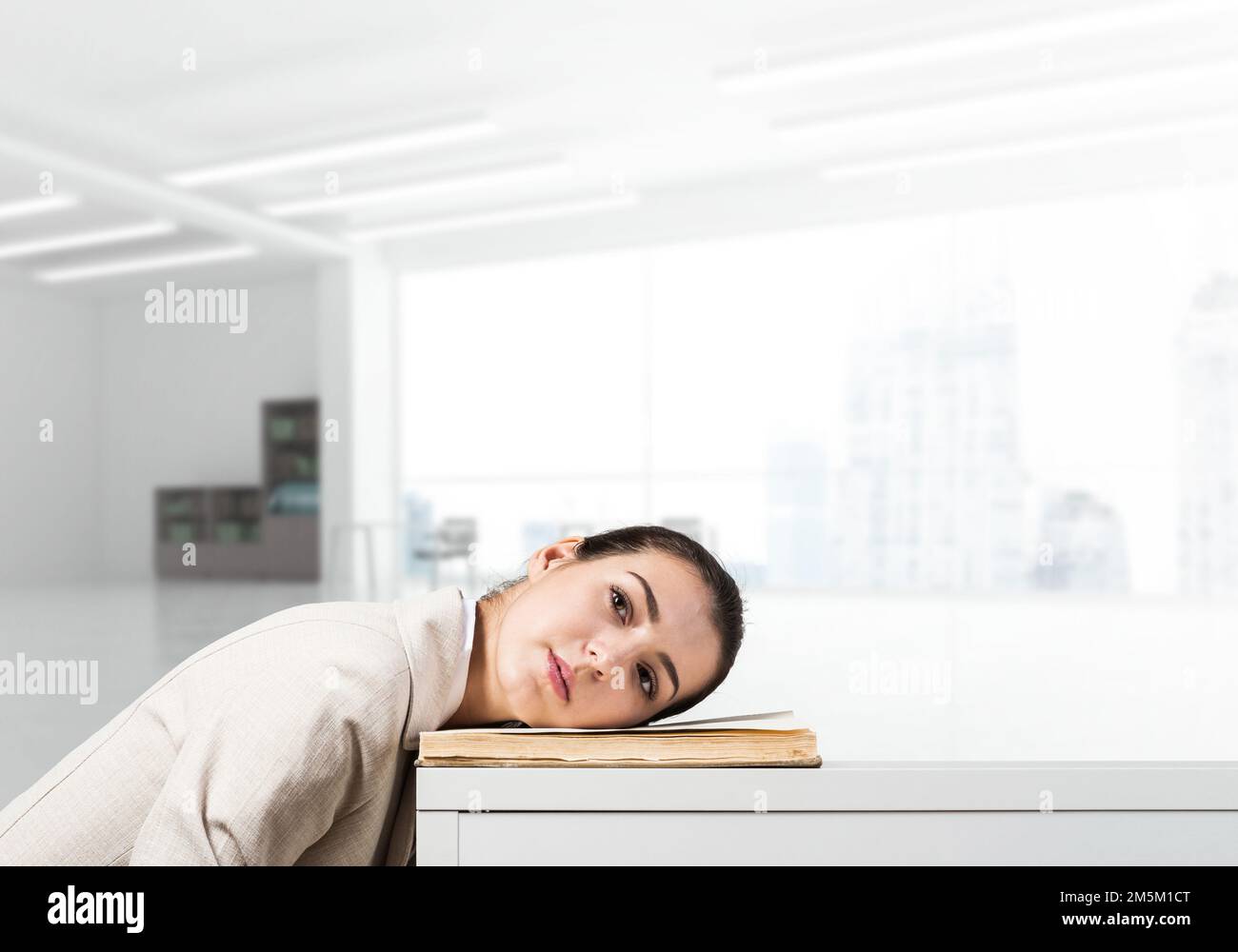 Bored business woman lying on desk Stock Photo - Alamy