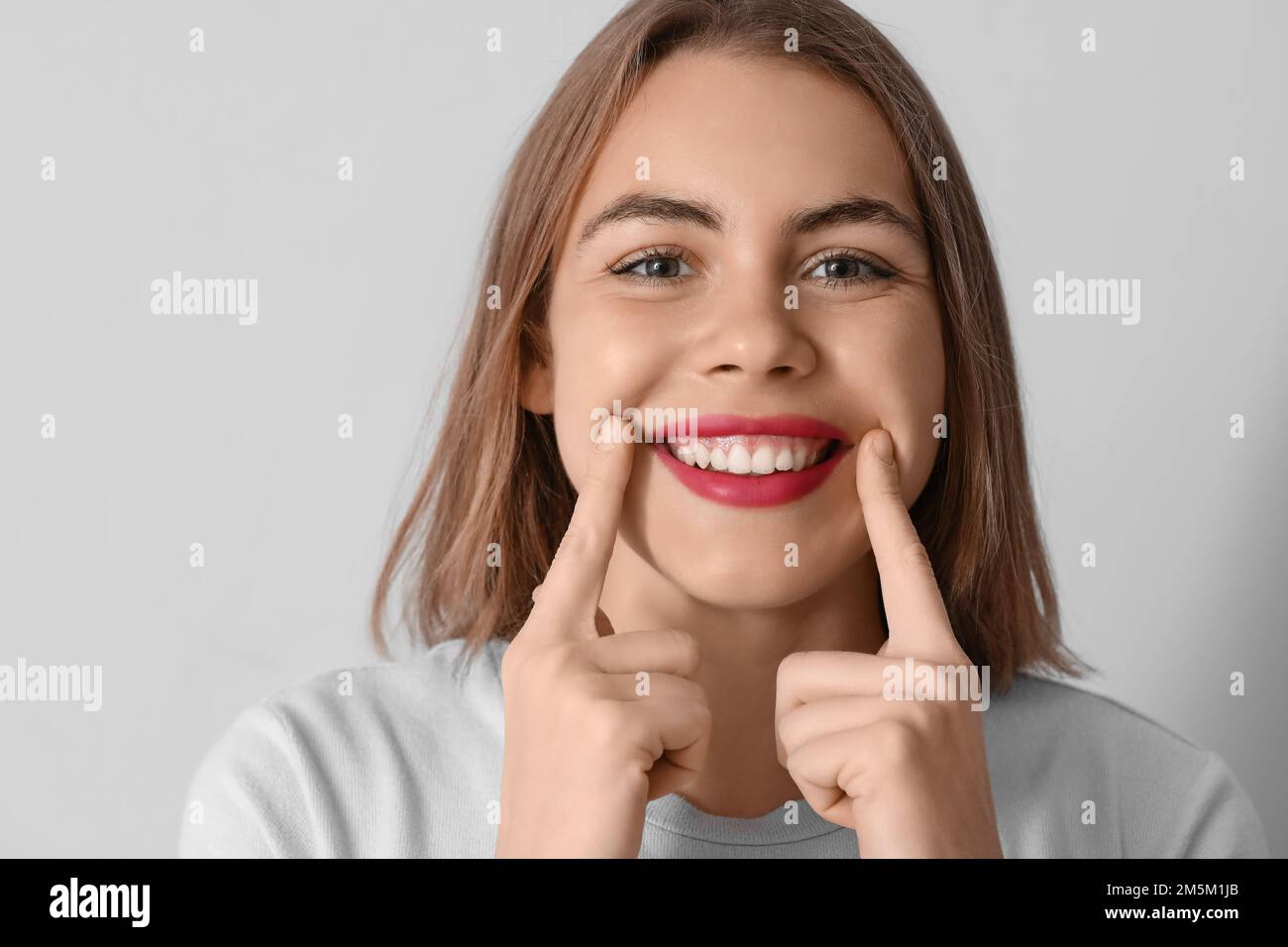 Young woman with beautiful smile on grey background, closeup Stock ...