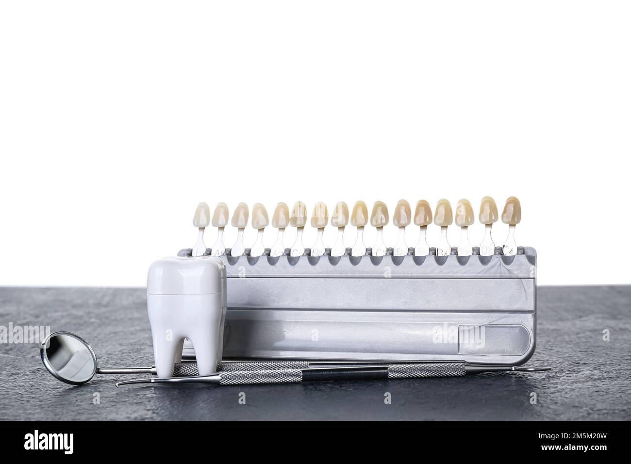 Teeth color samples with dental tools on dark table against white ...