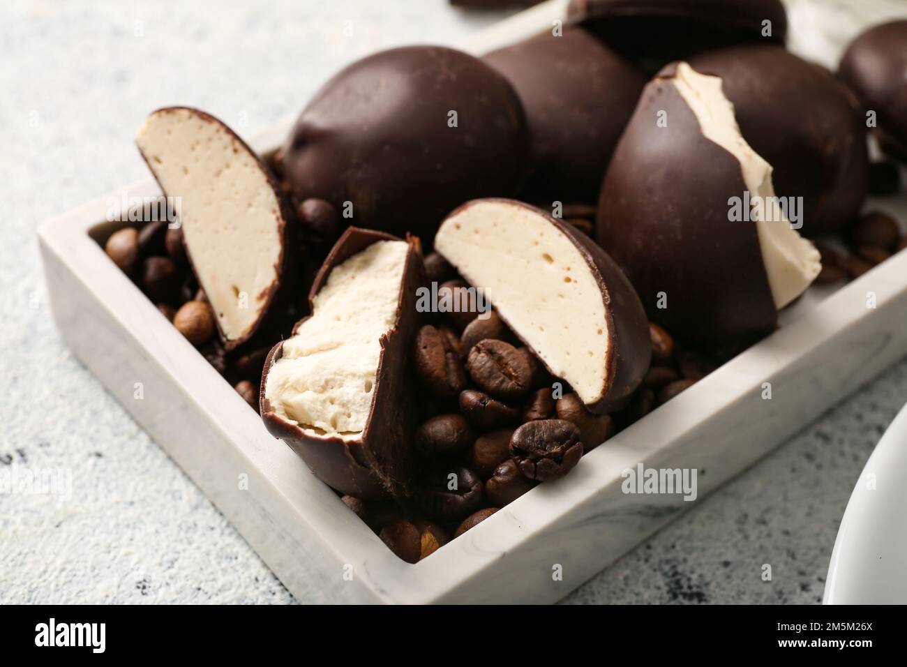 Board with tasty bird's milk candies and coffee beans on light ...