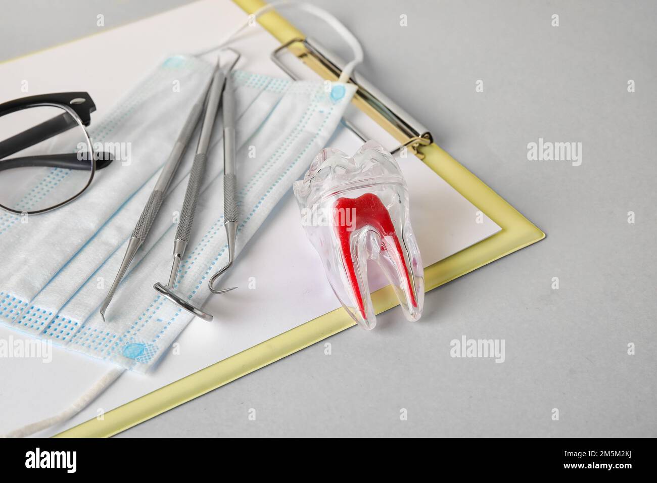 Plastic tooth with dental tools, medical mask and clipboard on grey ...
