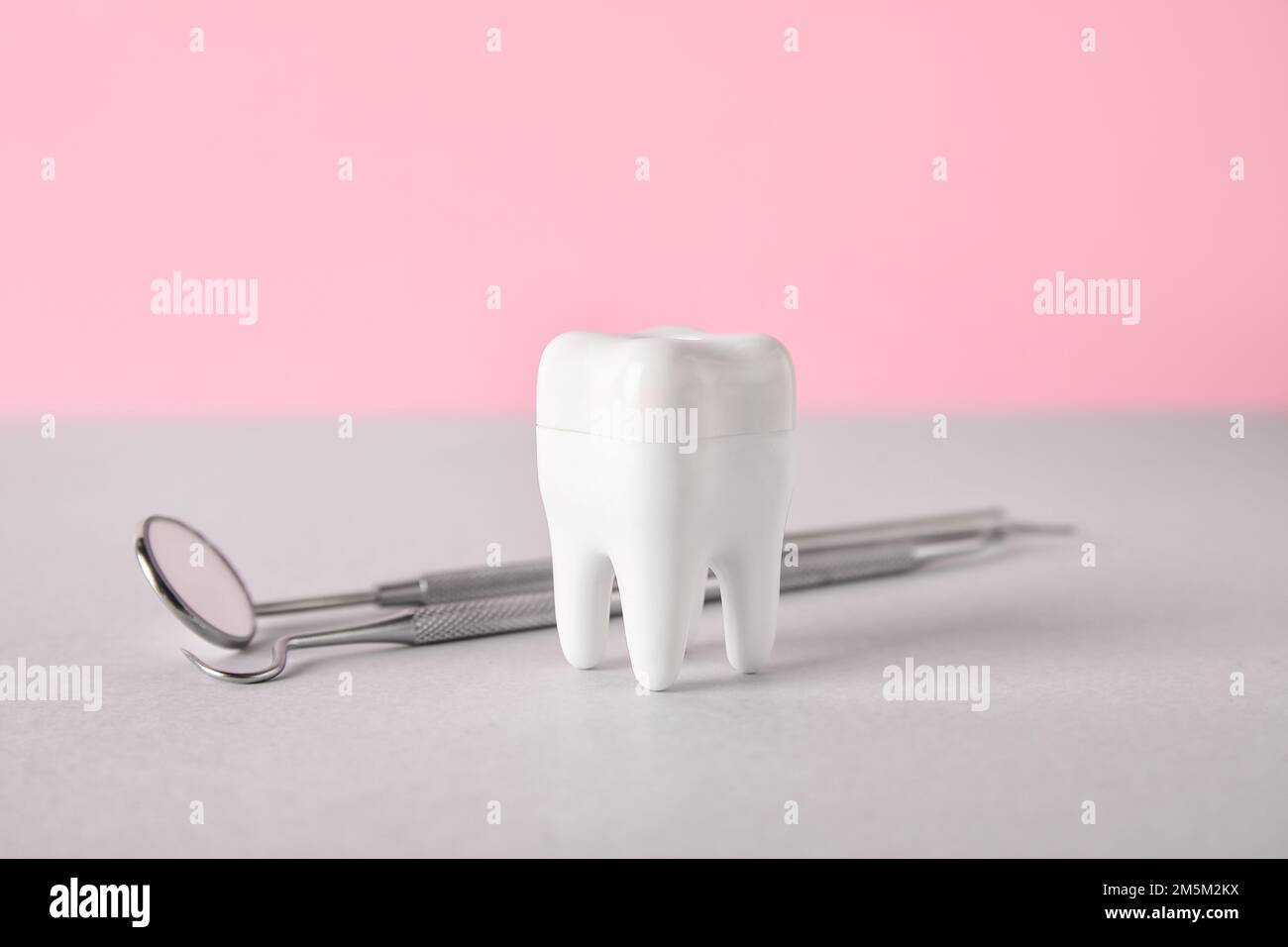 Plastic tooth with dental tools on table against pink background Stock ...
