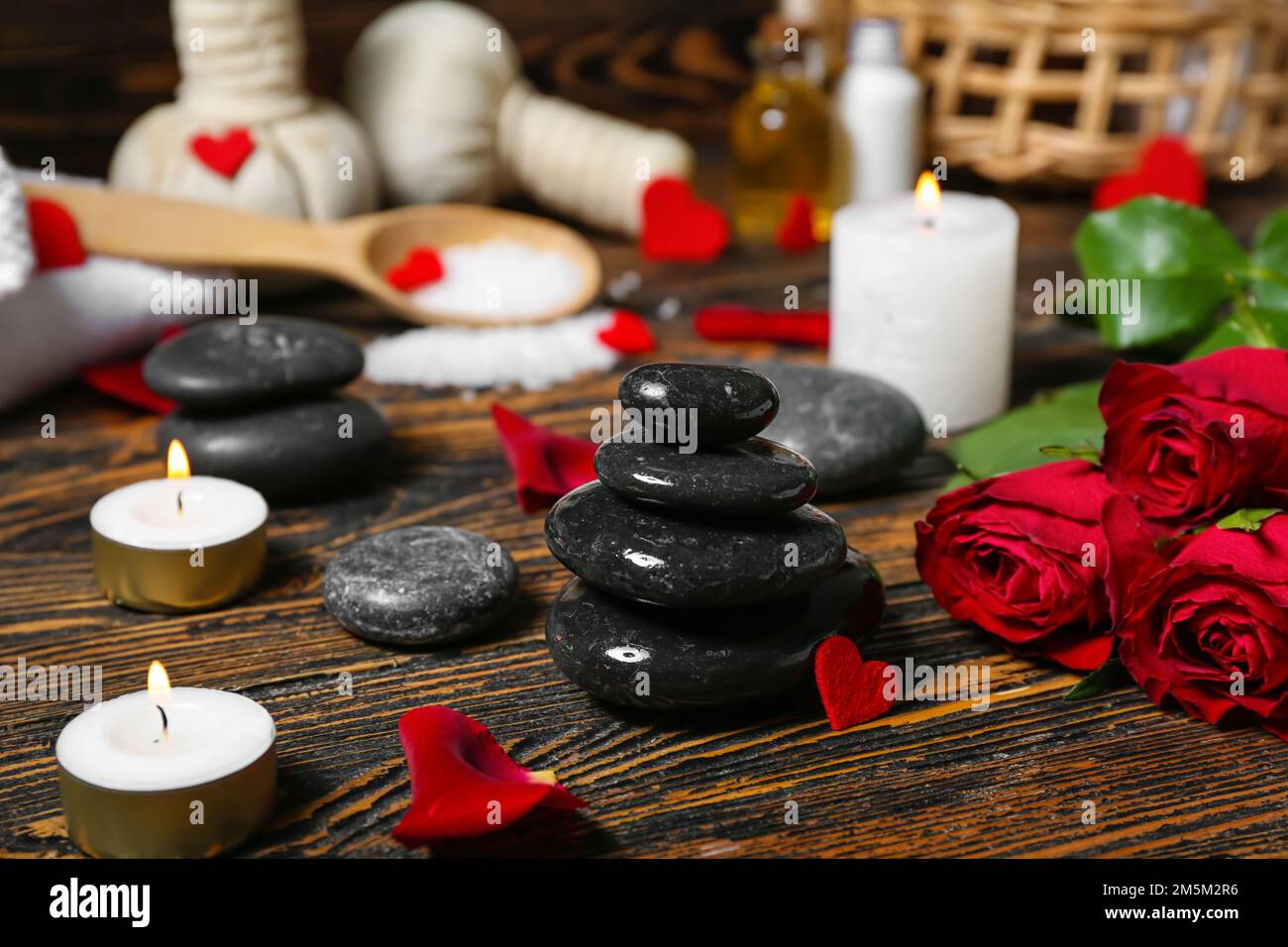 Spa stones with candles and roses on dark wooden table, closeup ...