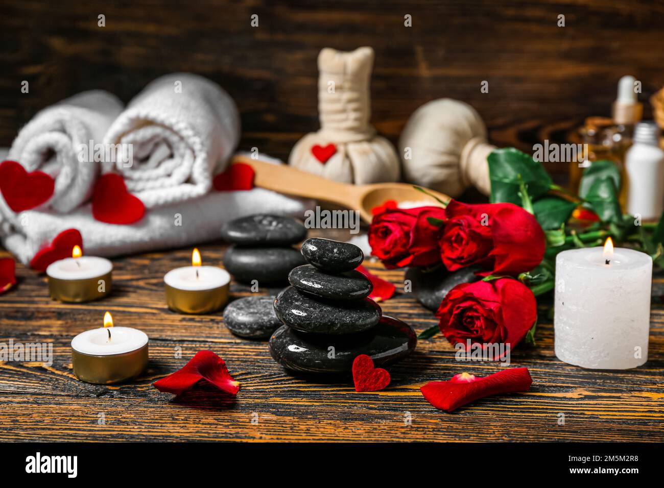 Spa stones with candles and roses on dark wooden table, closeup ...