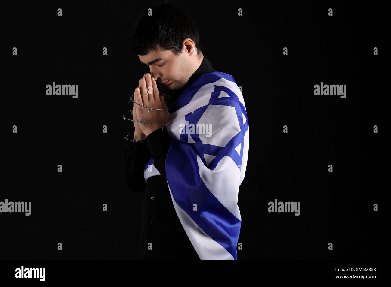 Praying Jewish man with flag of Israel and barbed wire honoring victims ...