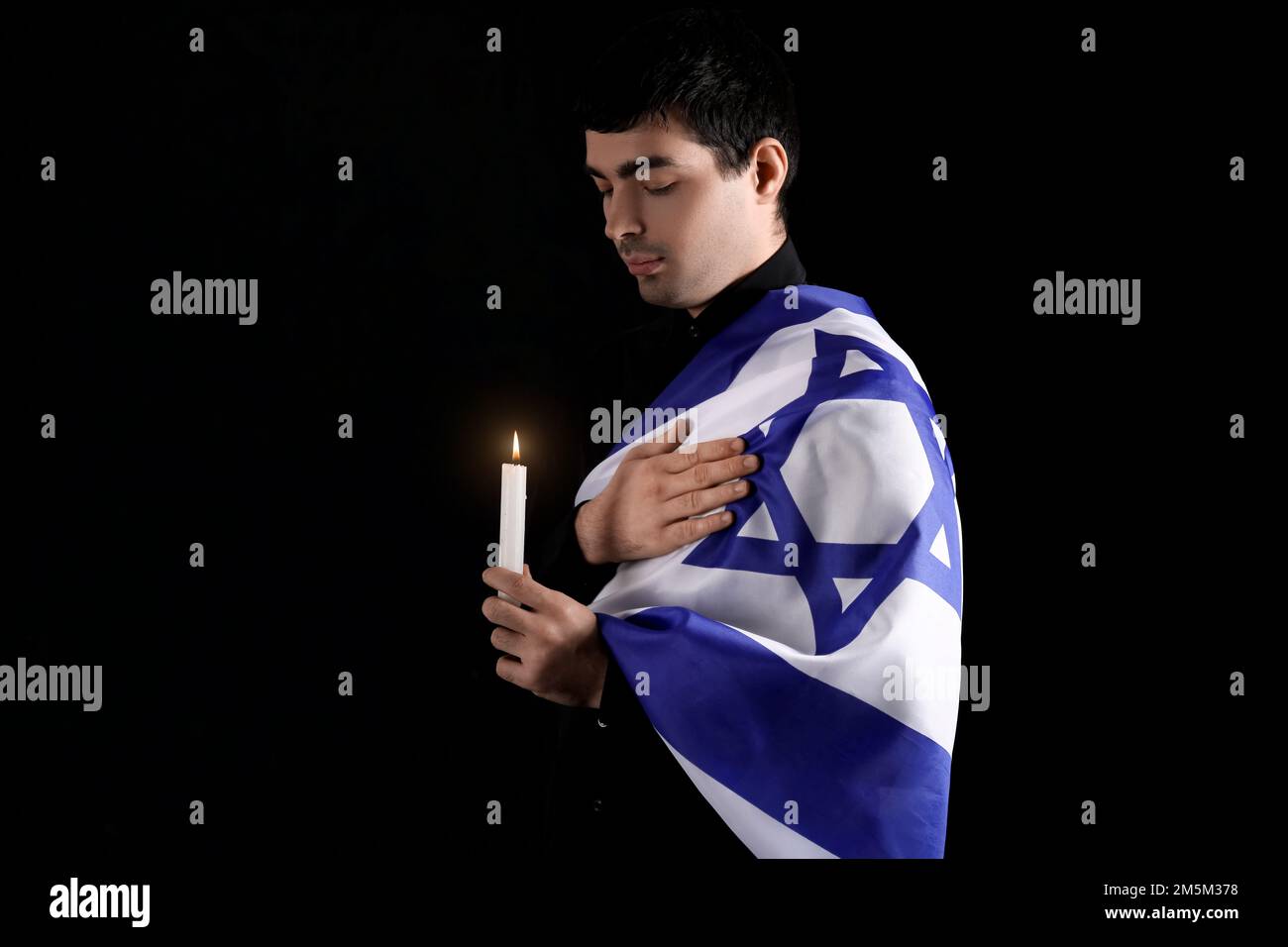 Jewish man with candle and flag of Israel honoring victims of Holocaust ...