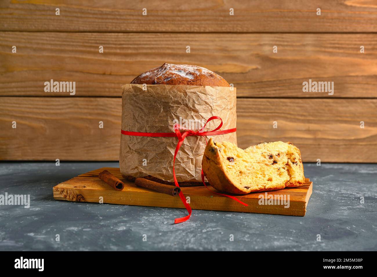 Board with Panettone and cinnamon on table near wooden wall Stock Photo ...