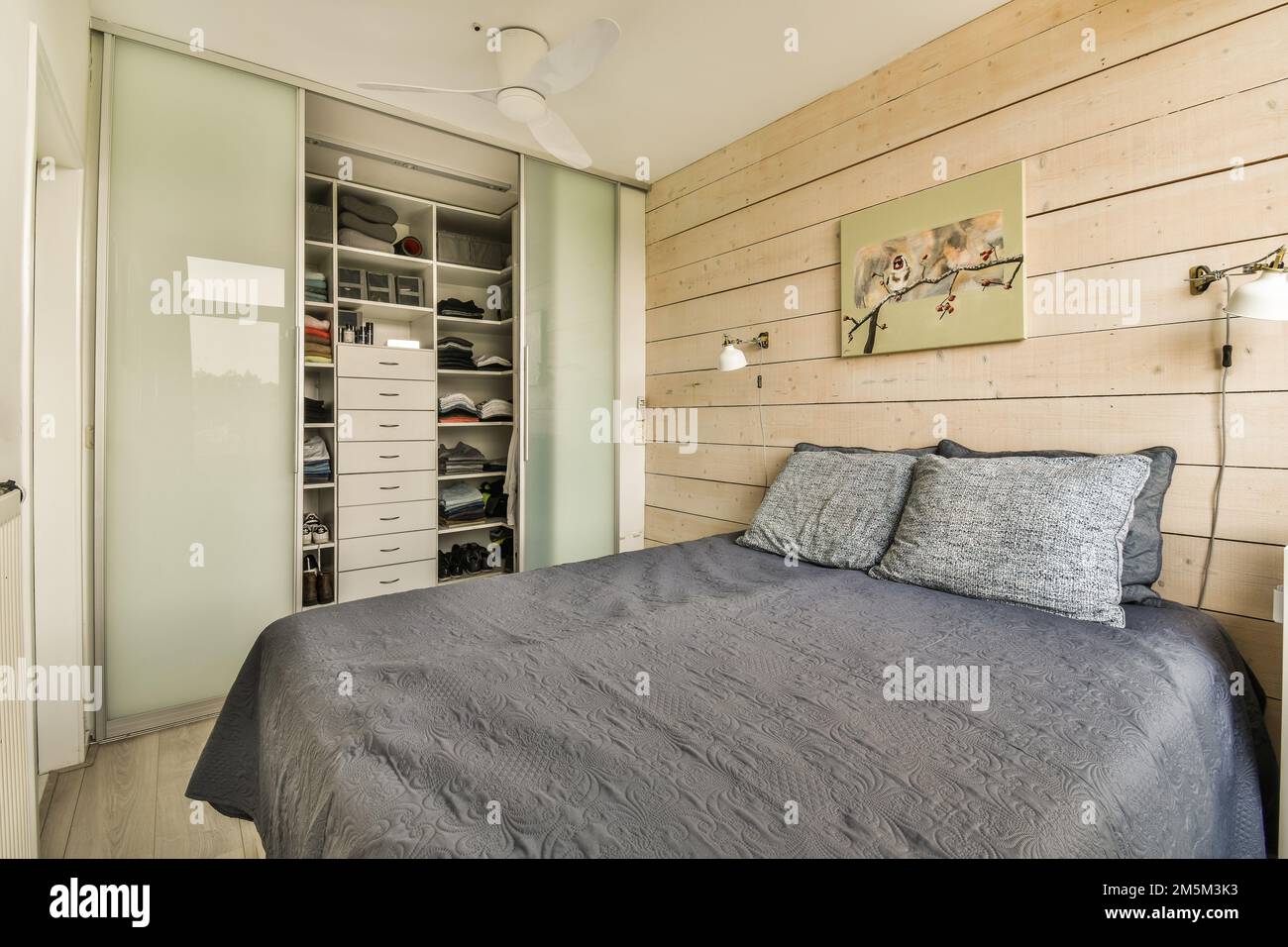 a bedroom with wood paneling on the walls, and a bed that has a blue ...