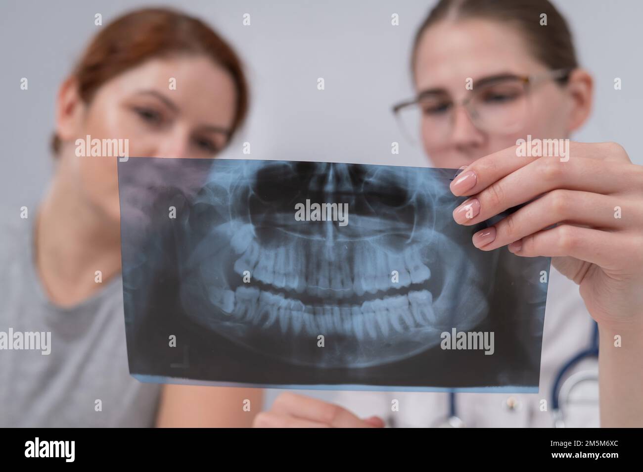 A woman doctor and a patient at the reception are discussing an x-ray ...