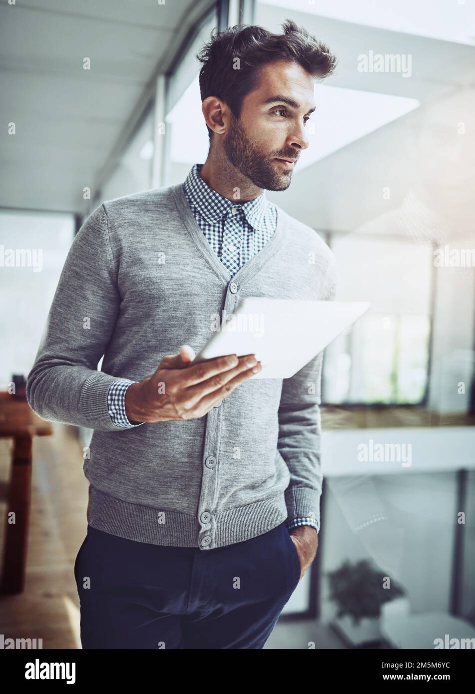 I wonder...a handsome young businessman using his digital tablet while ...