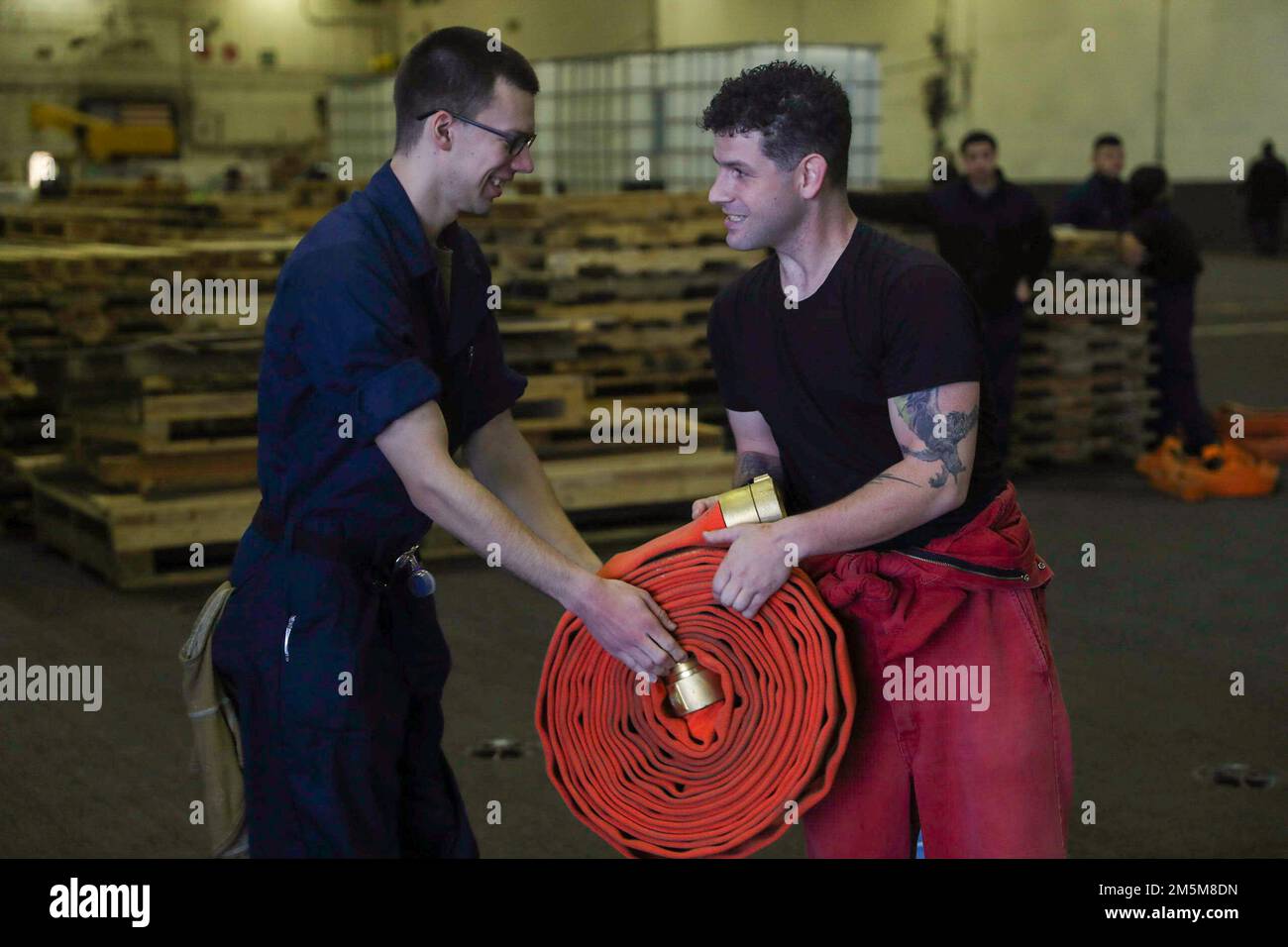 Damage Controlman Fireman Ethan Voss, left, from Abilene, Texas, hands ...