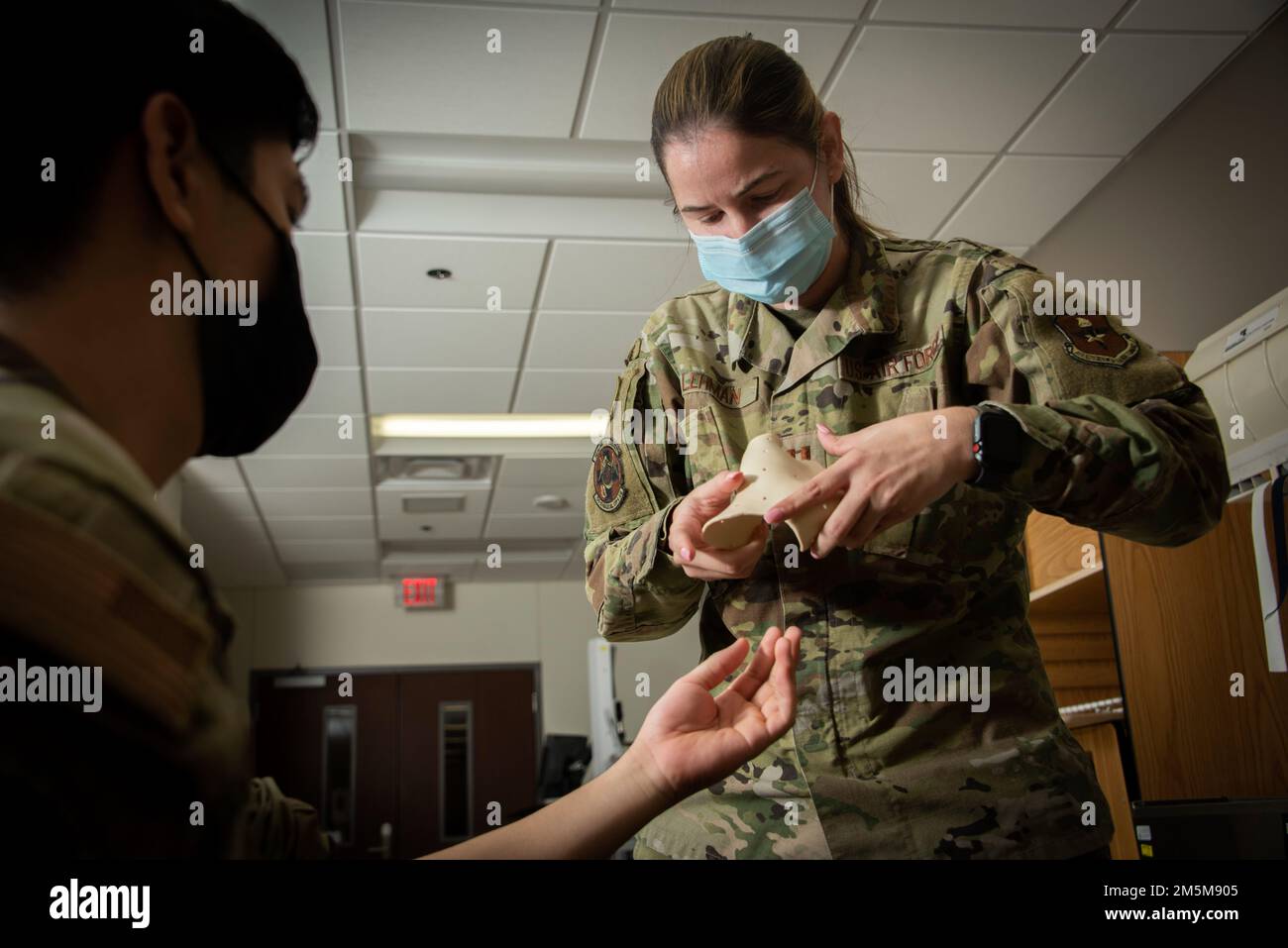 Capt. KaRena Lehman, staff occupational therapist, fits a patient with ...