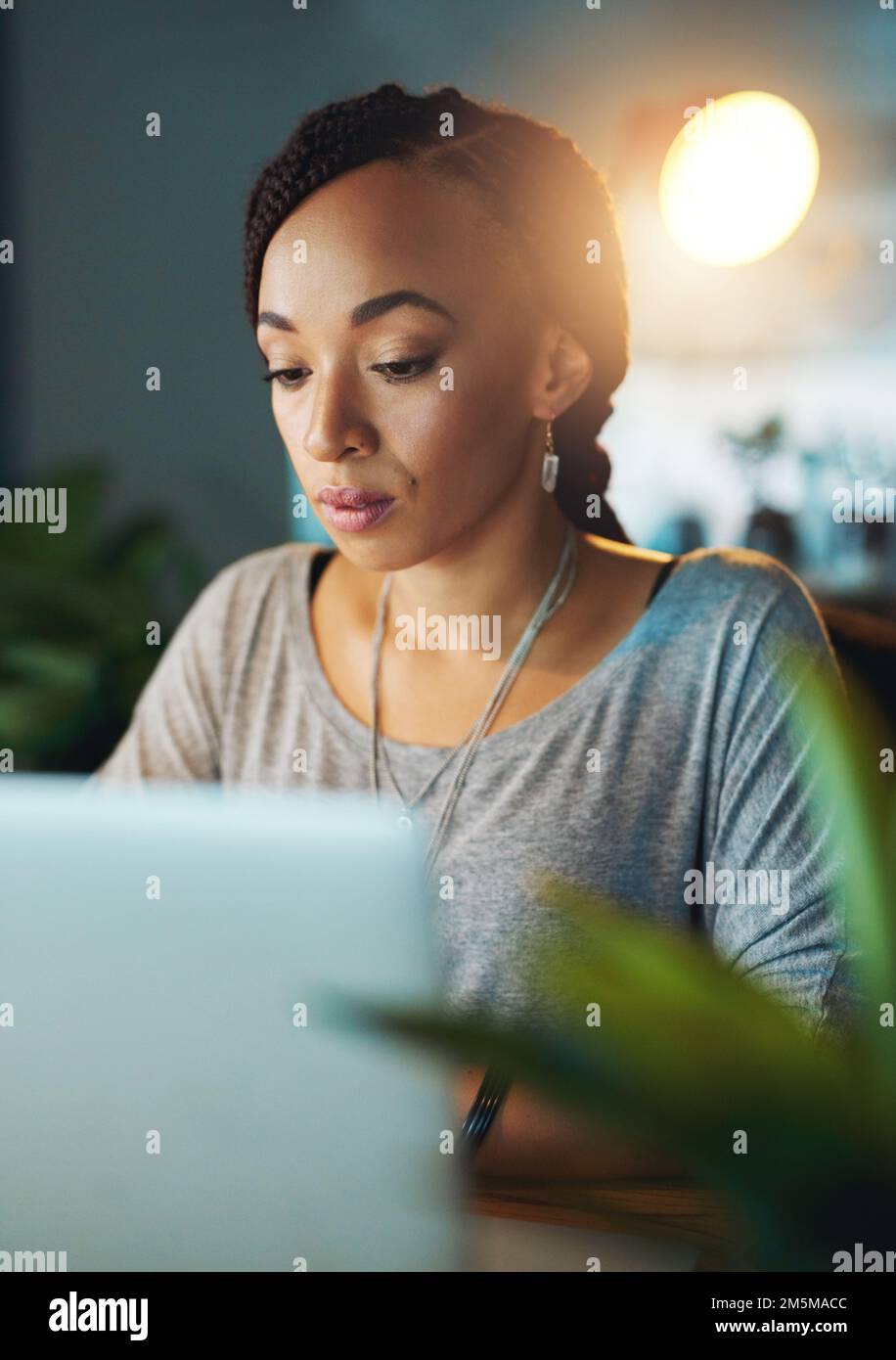 Working late into the night. a young woman using her laptop while ...