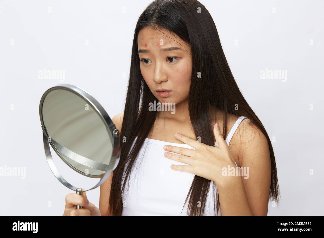 Asian woman with mirror in hand facial skin problems, acne and ...