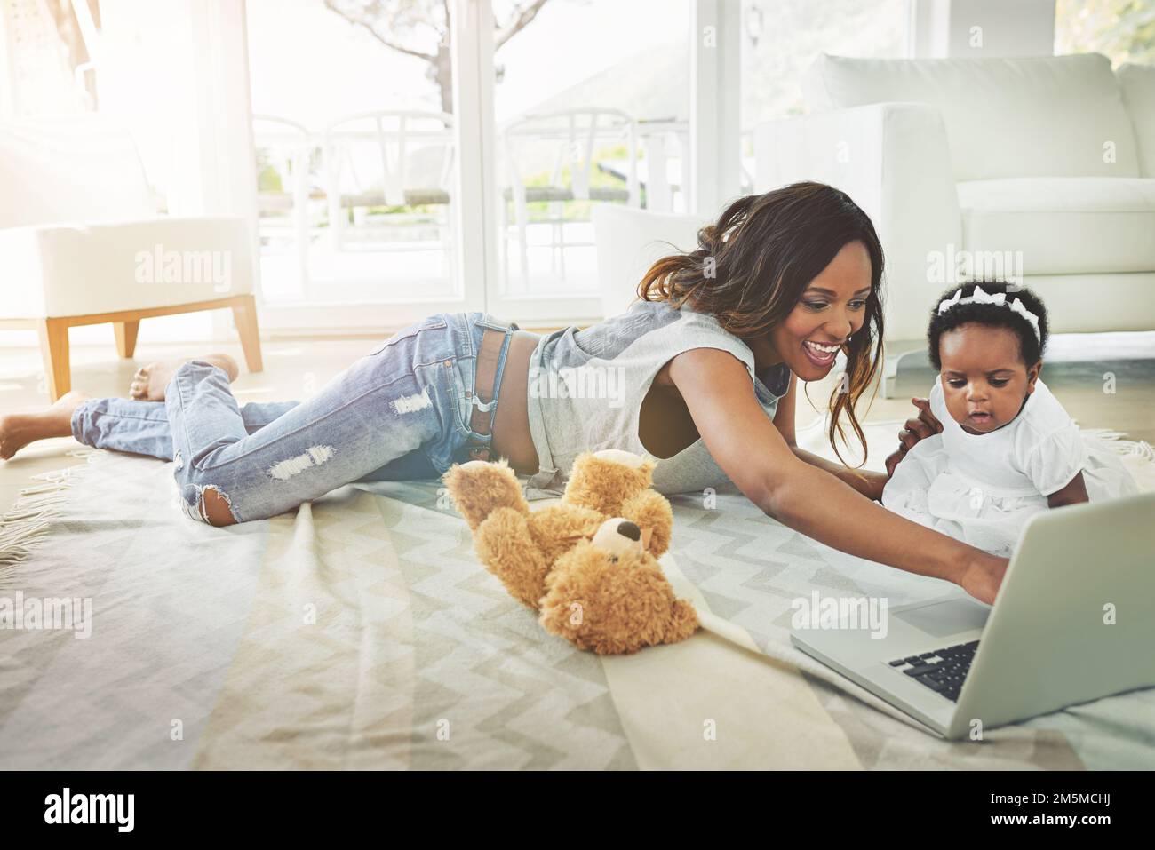 Teaching through technology. a mother using a laptop with and her baby ...