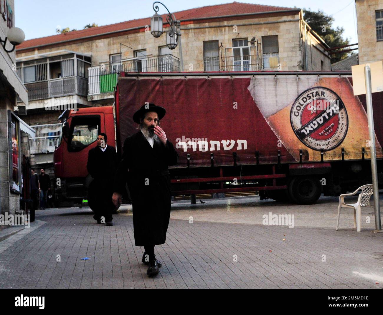 An Orthodox Jewish man standing by an advertisement for a famous ...