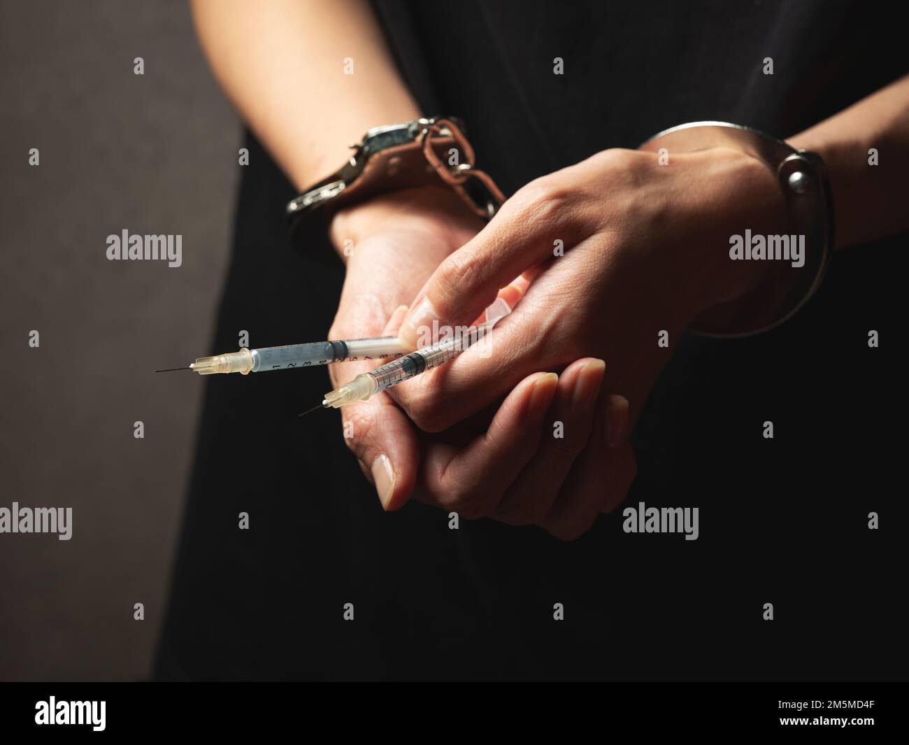 Handcuffs on wrist, drug syringe Stock Photo - Alamy
