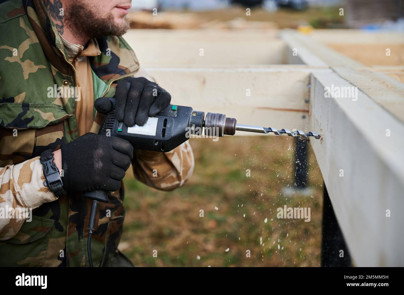Man building wooden frame house on pile foundation. Close up of male ...