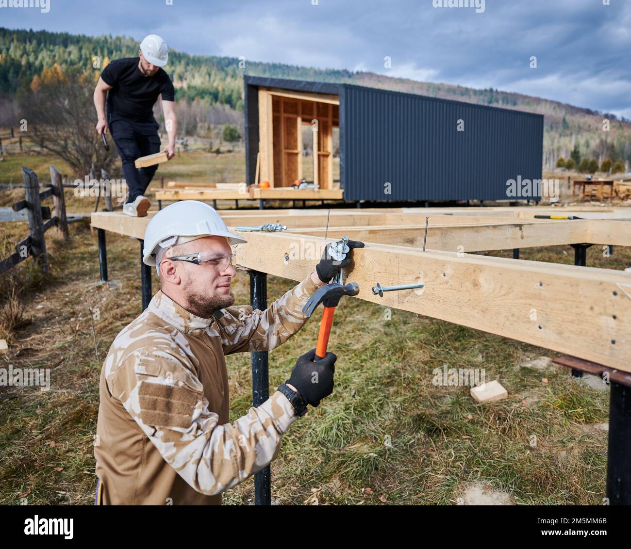 Man worker building wooden frame house on pile foundation. Carpenter ...
