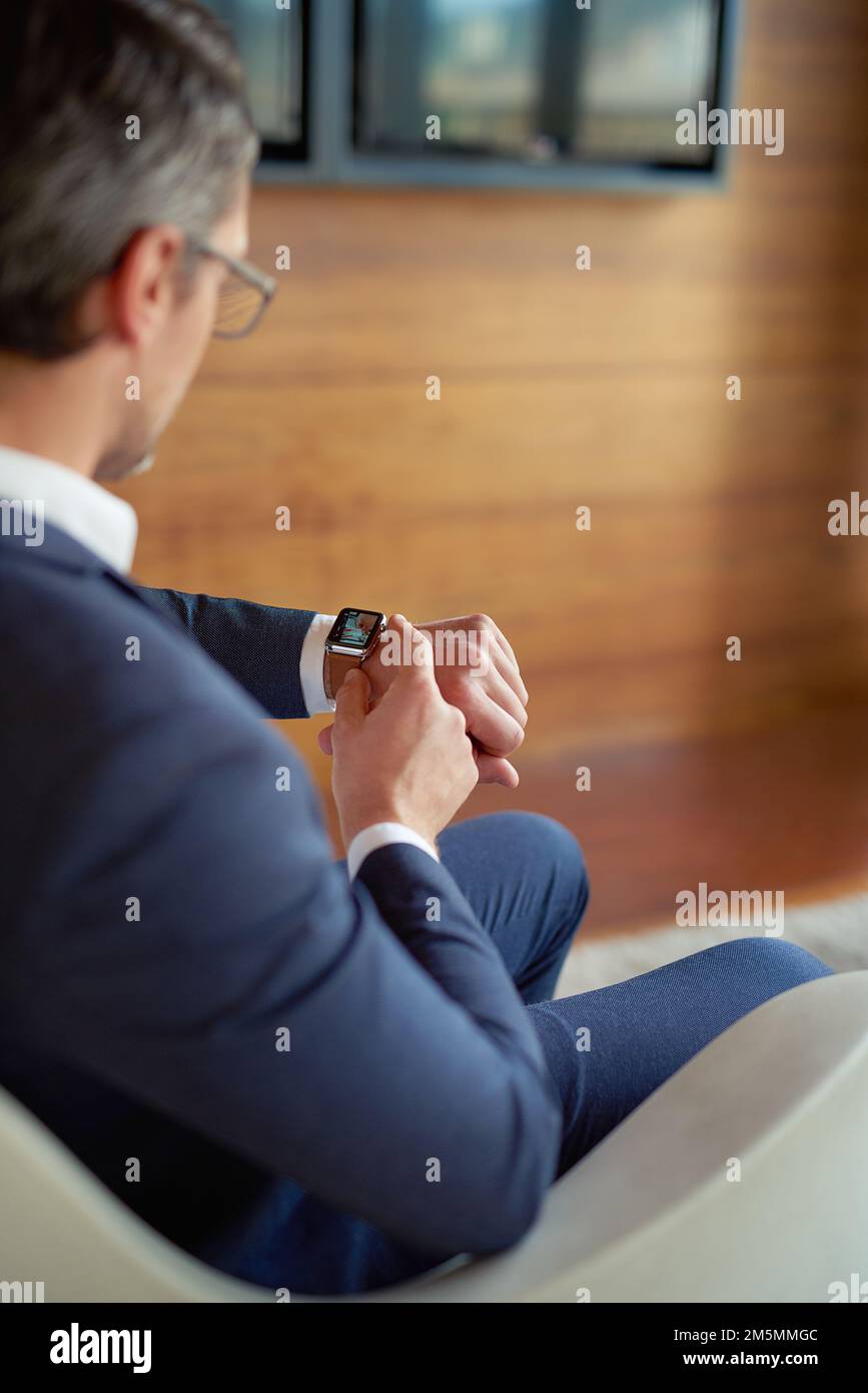 Time is money. a businessman checking his watch while sitting in a ...