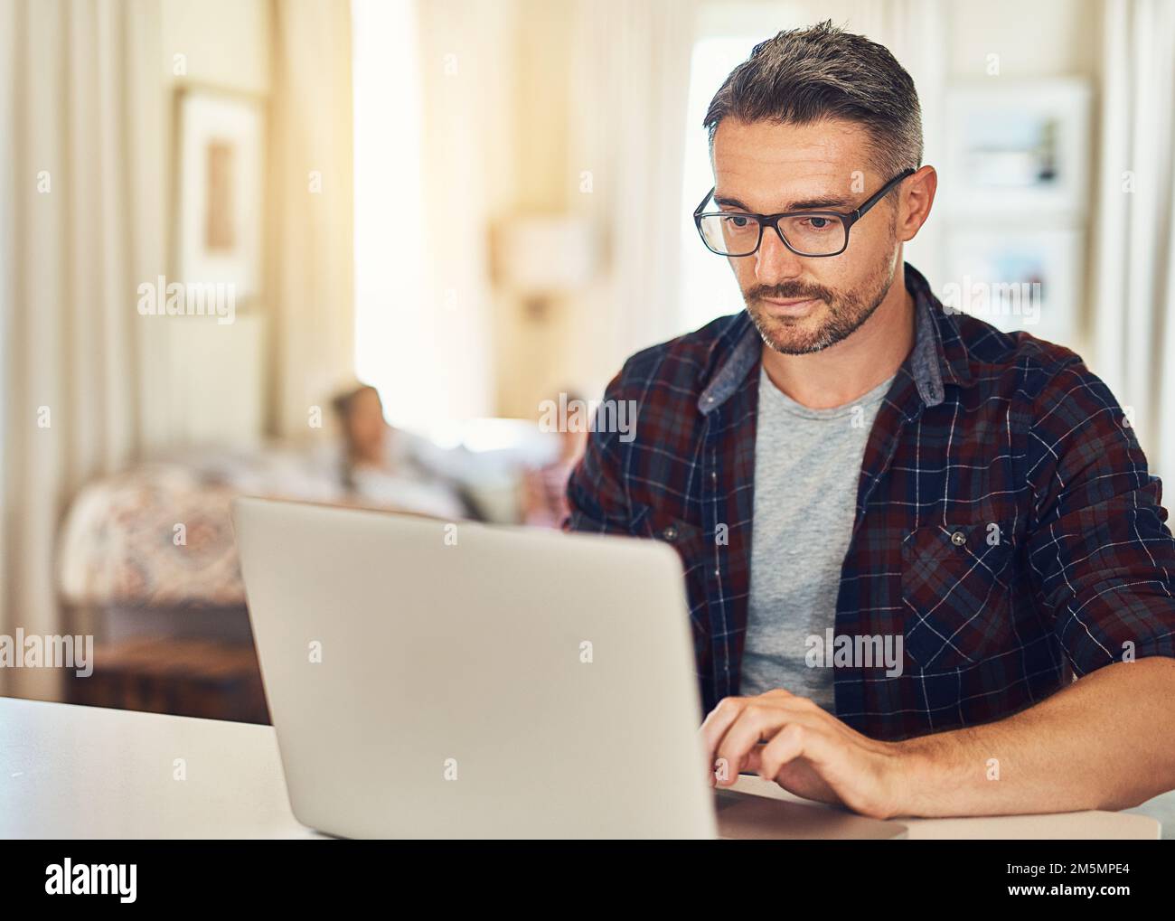 Getting a little work done at home. a mature man using a laptop at home ...