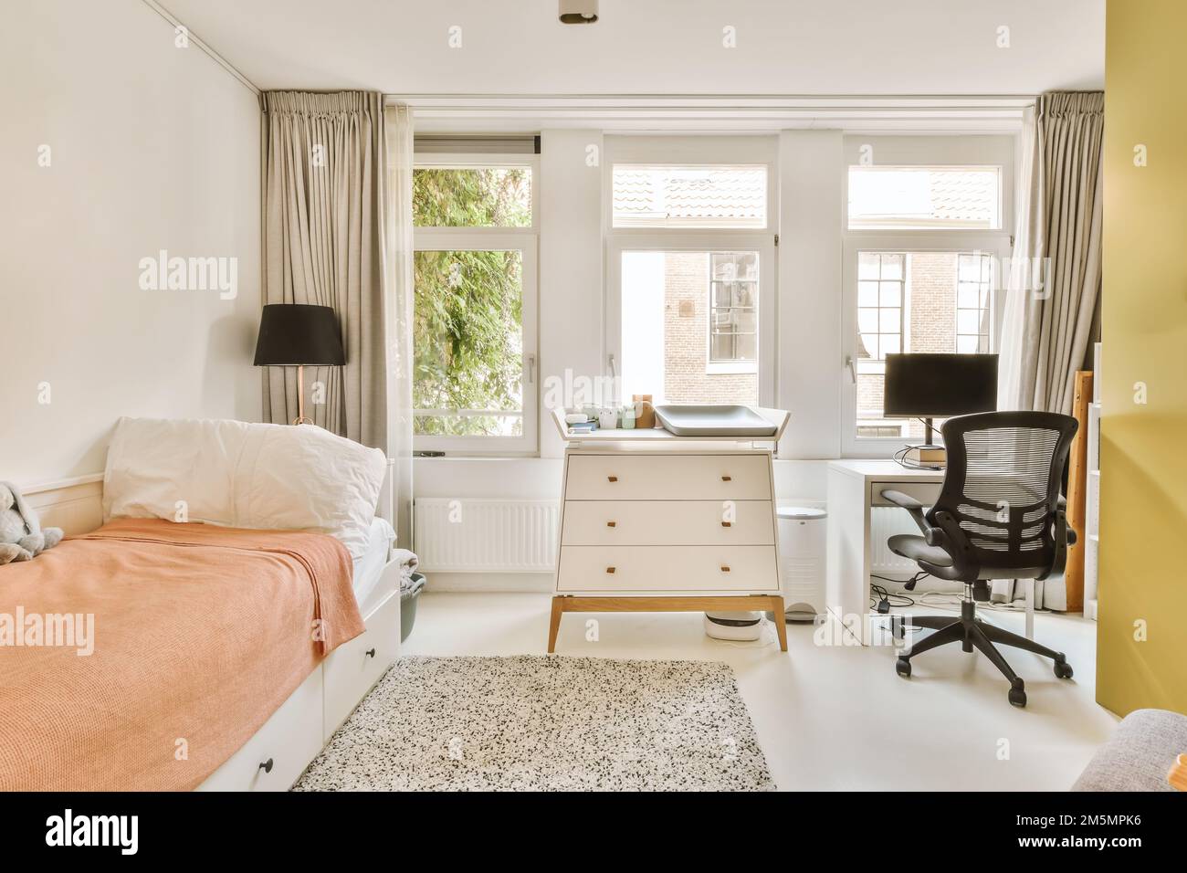 a bedroom with a bed, desk and computer on the table in front of the ...