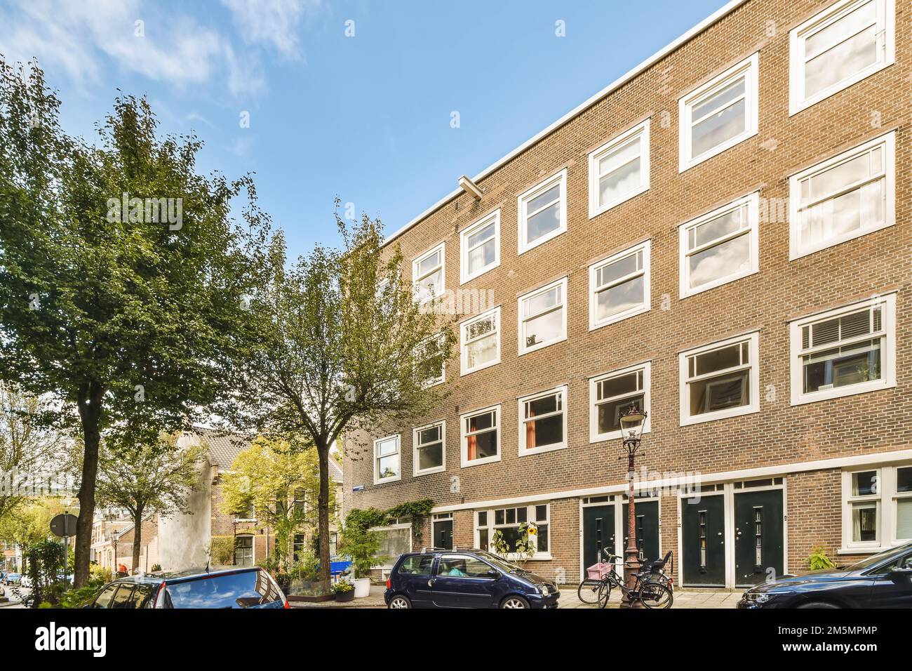 an apartment building with cars parked on the street in front of it and ...