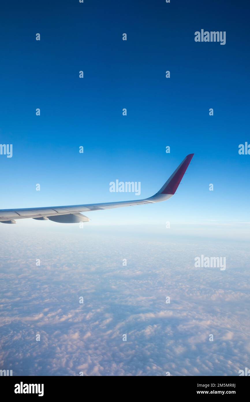 A vertical closeup shot of a wings of an airplane in white and red ...