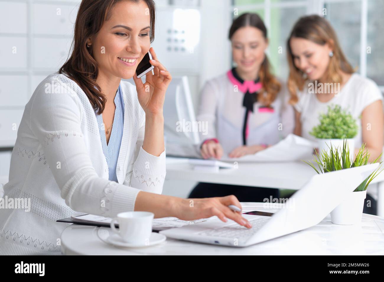 young women sit at the table and work in a modern office Stock Photo ...