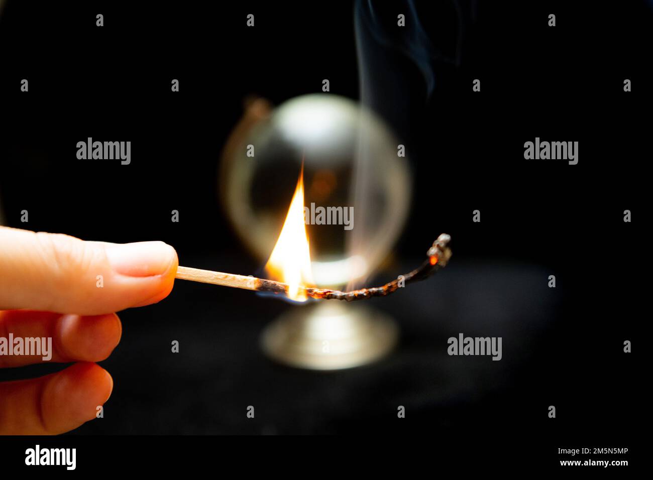 A closeup shot of a match with fire and a globe on the black background ...