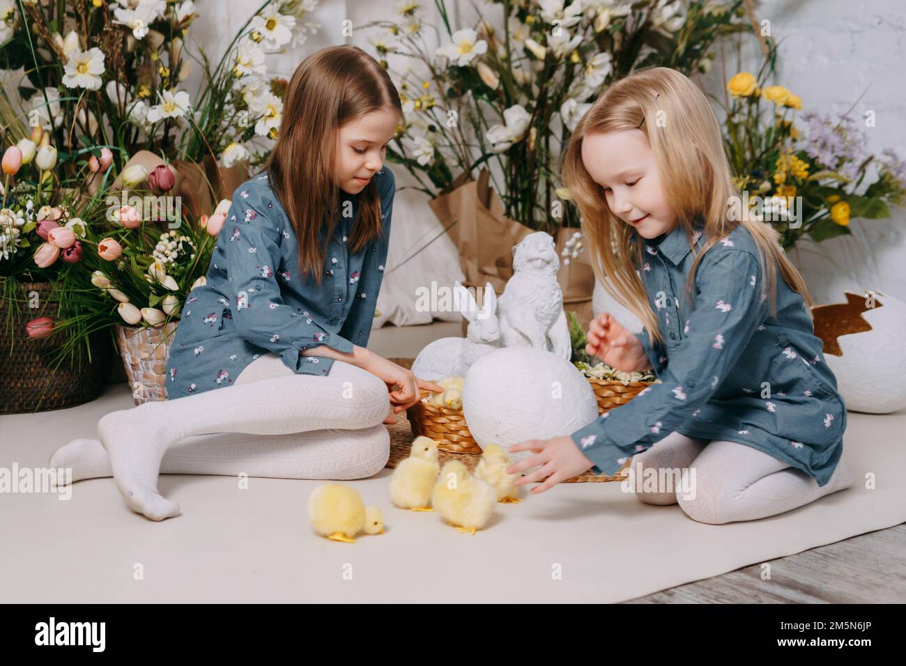 Two girls in a beautiful Easter photo zone with flowers, eggs, chickens ...