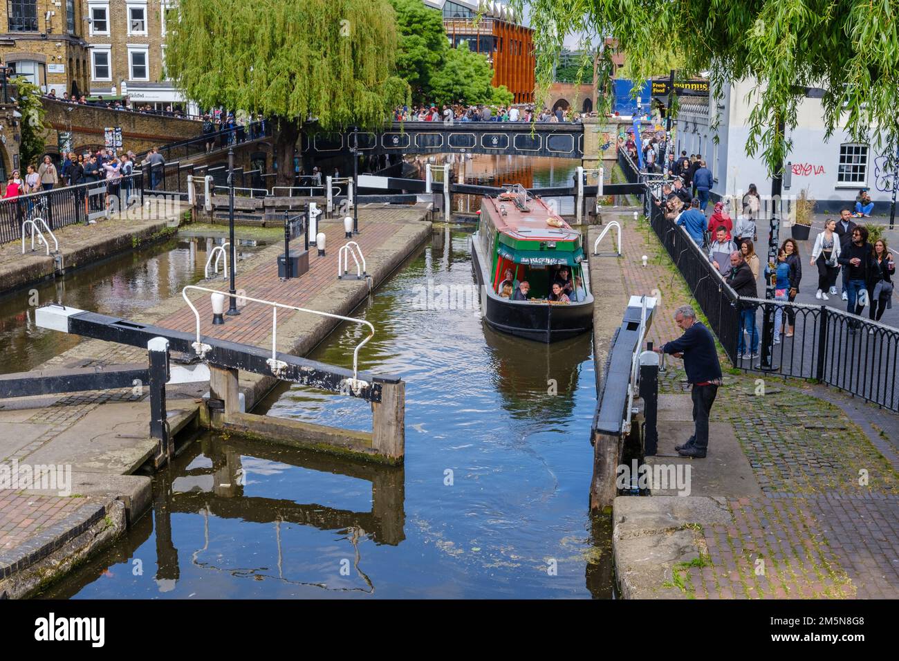 A man opens the lock gate while a leisure narrowboat waits in the lock ...