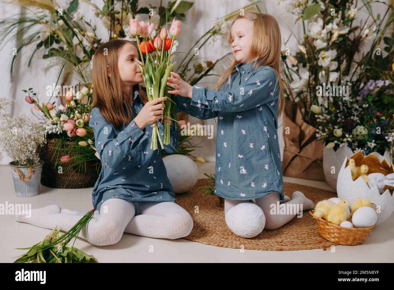 Two girls in a beautiful Easter photo zone with flowers, eggs, chickens ...
