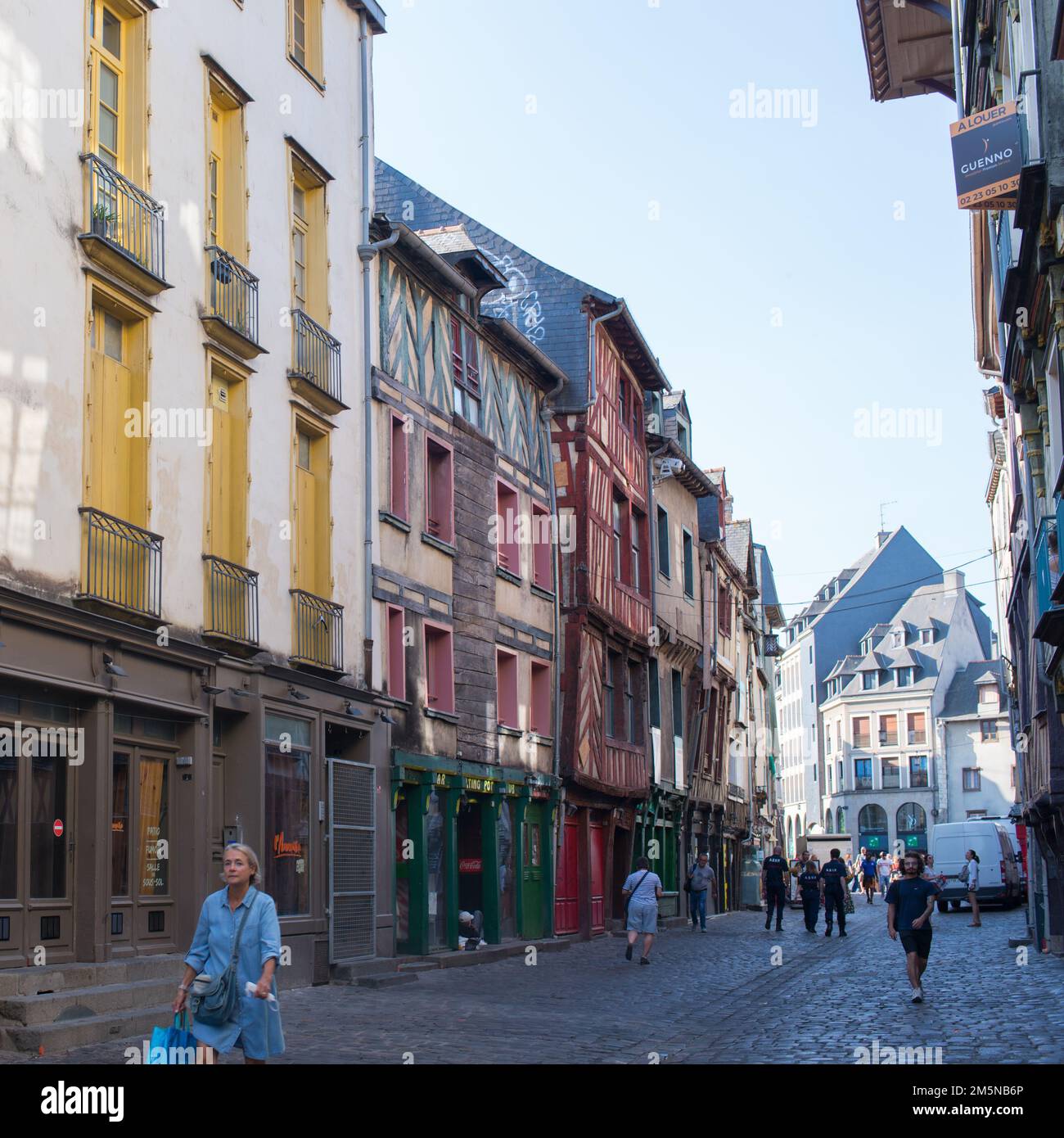 The people walking down a street in Rennes with beautiful buildings in ...