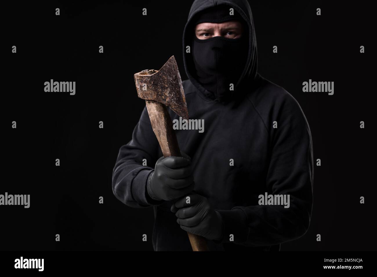 Bandit in black mask with hatchet on black background Stock Photo - Alamy